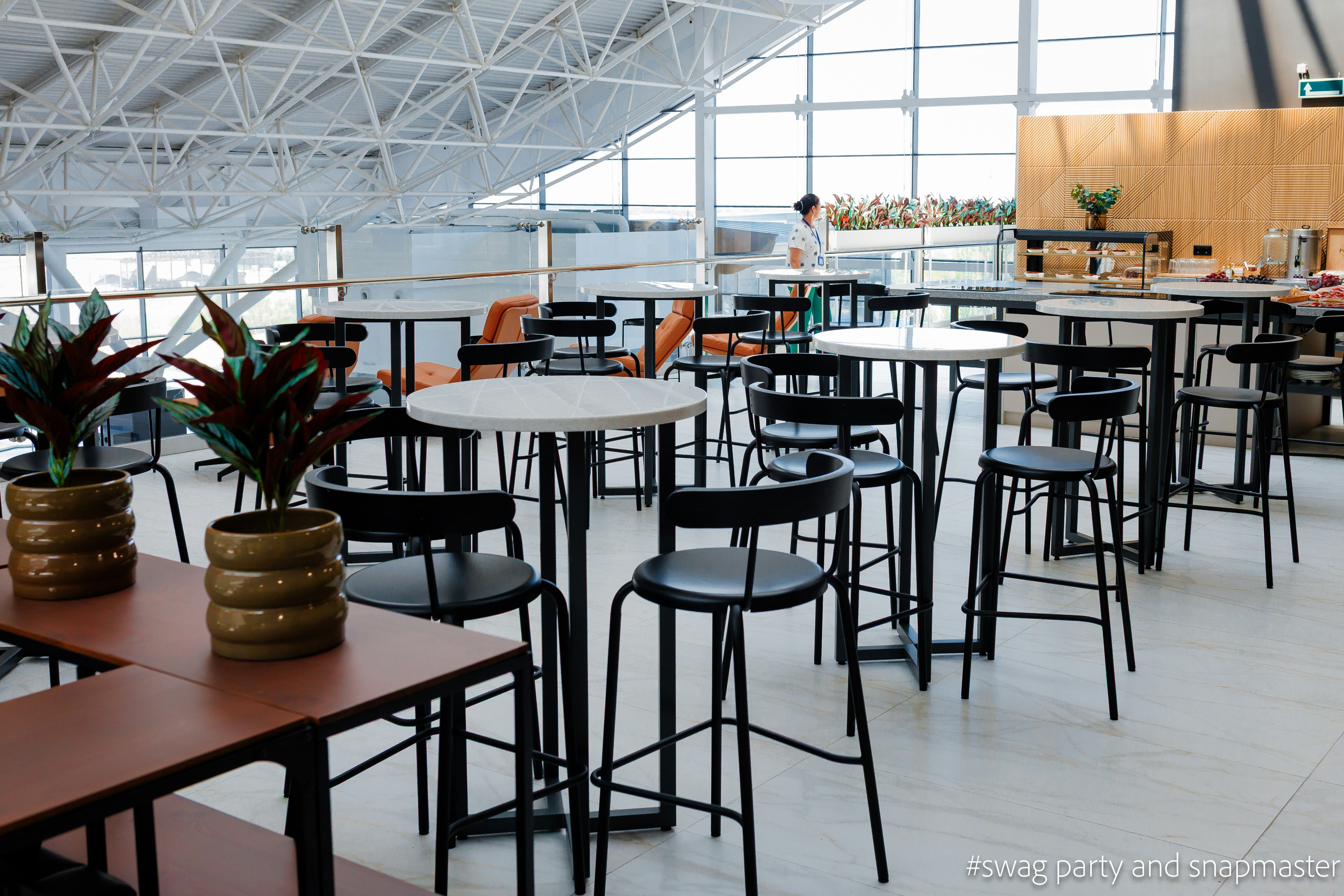 Sunlit rooftop café with scattered high stools and sleek tables