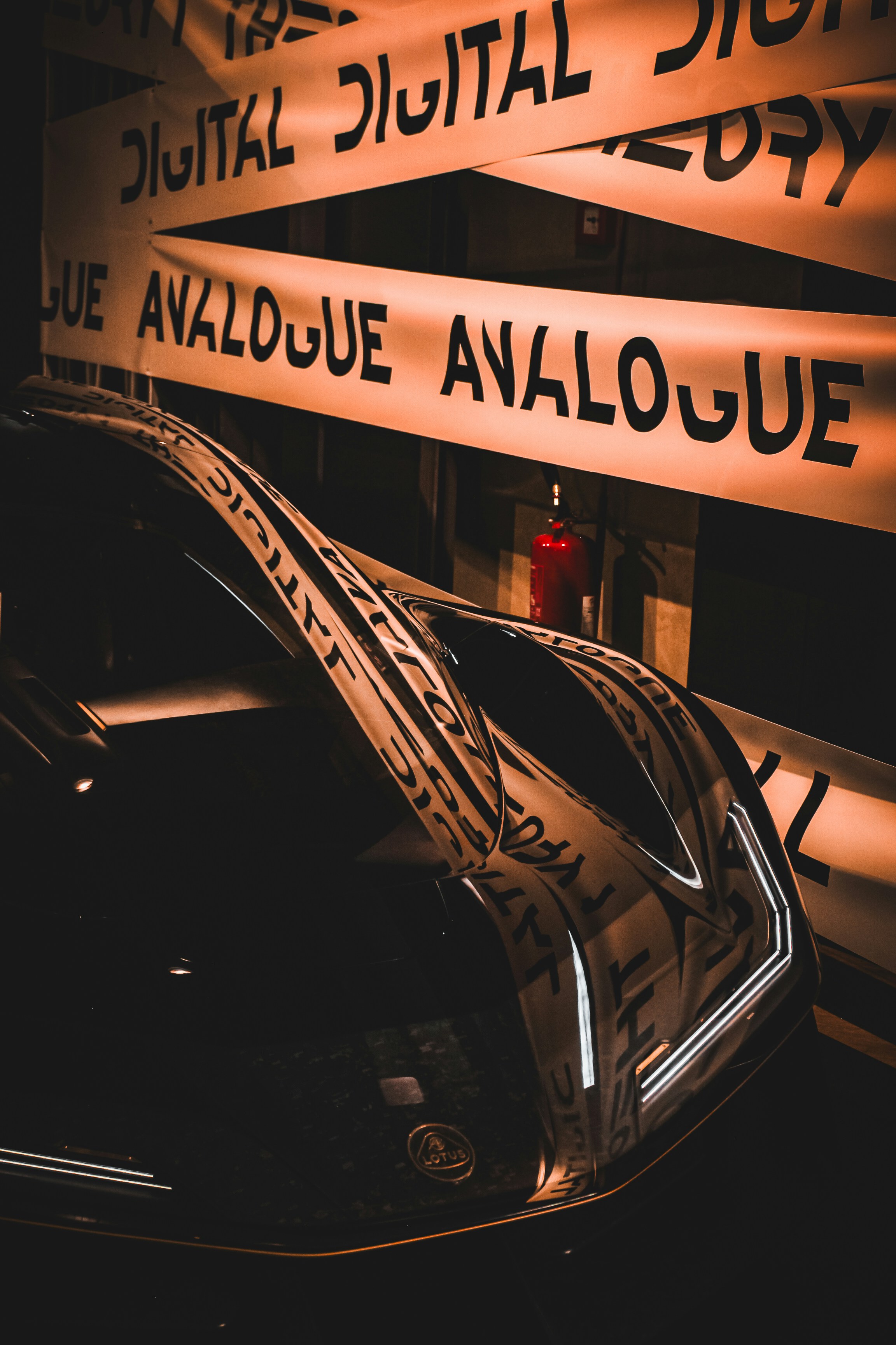 Ribbons of Orange Light Wrap a Sleek Car as Tape-Like Strips Crest Overhead