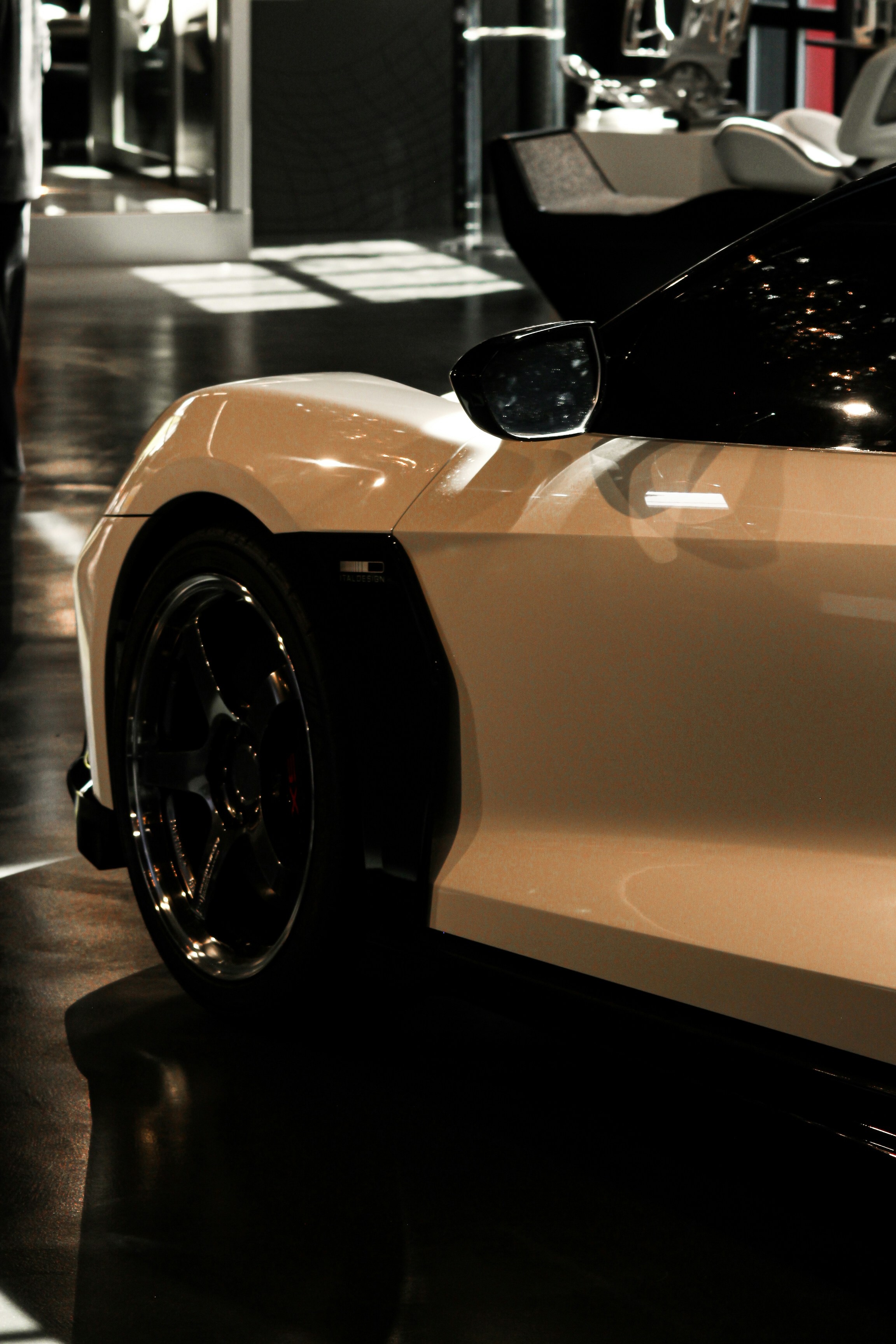 White sports car at a showroom edge: close-up on front wheel and door seam