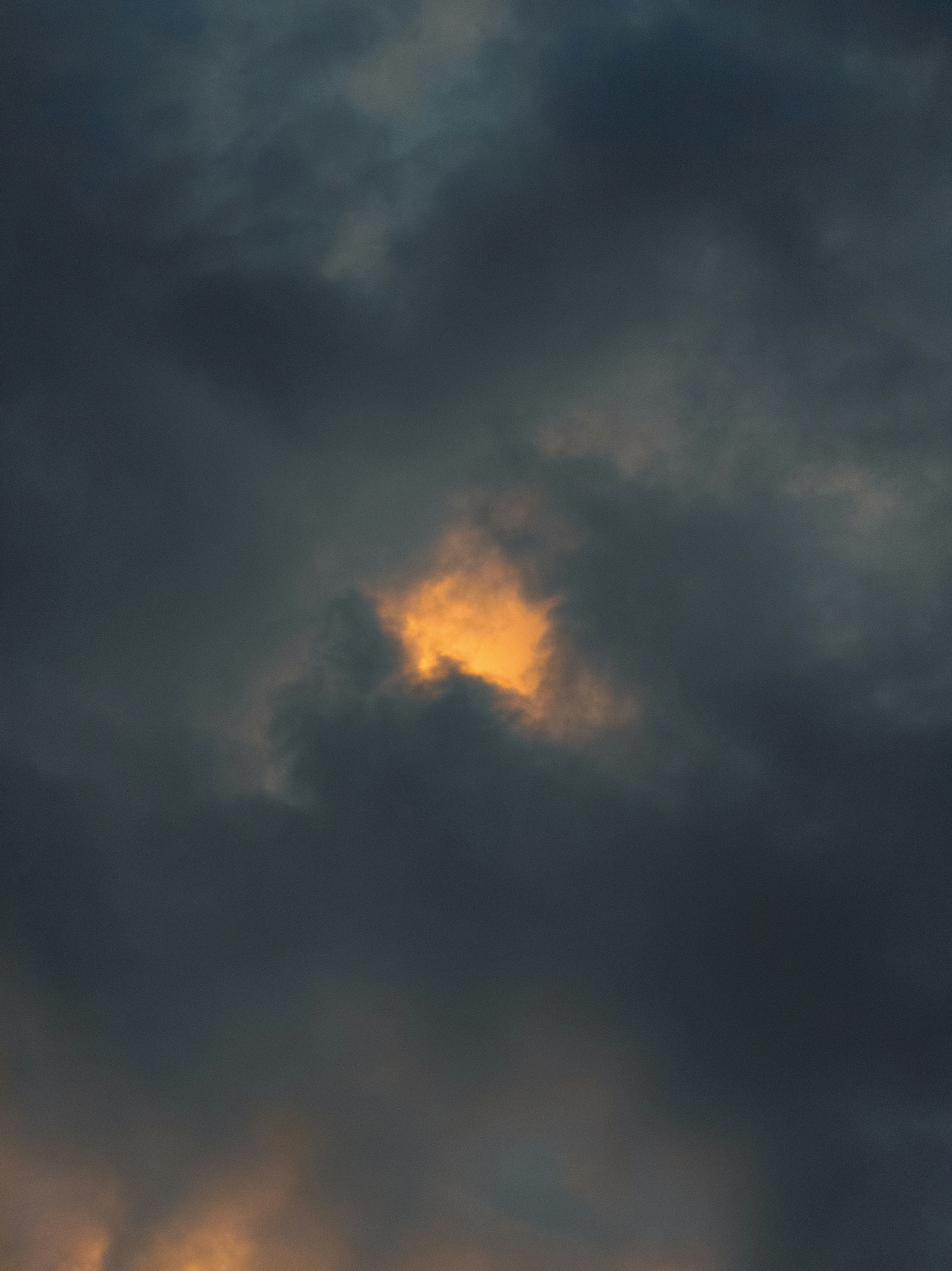 Dramatic sky with dark clouds and a bright orange gap, emphasizing the contrast between stormy tones and a hint of sunlight.