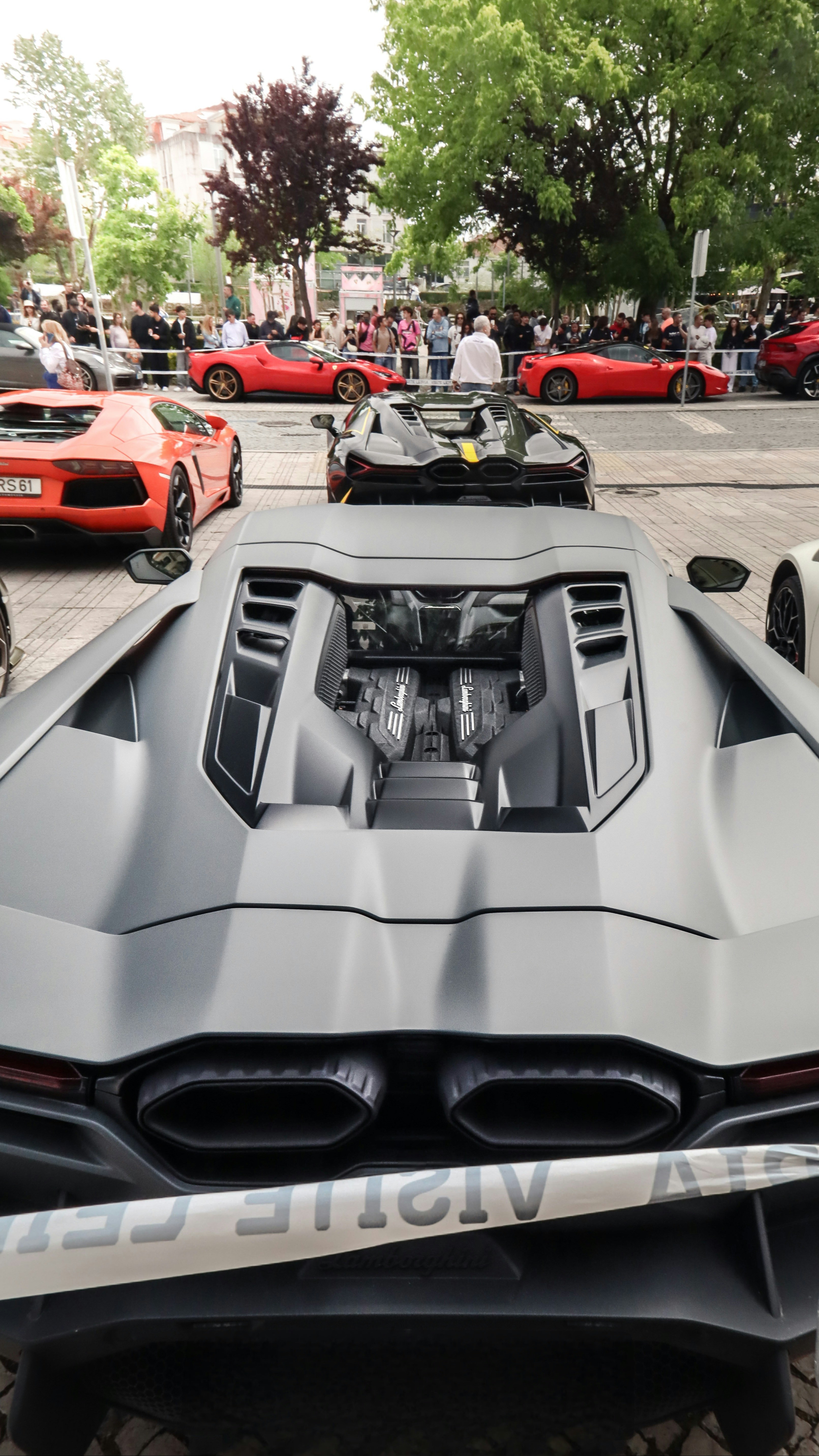 Midnight Matte: A Row of Hypercars Framed by a Street-side Crowd