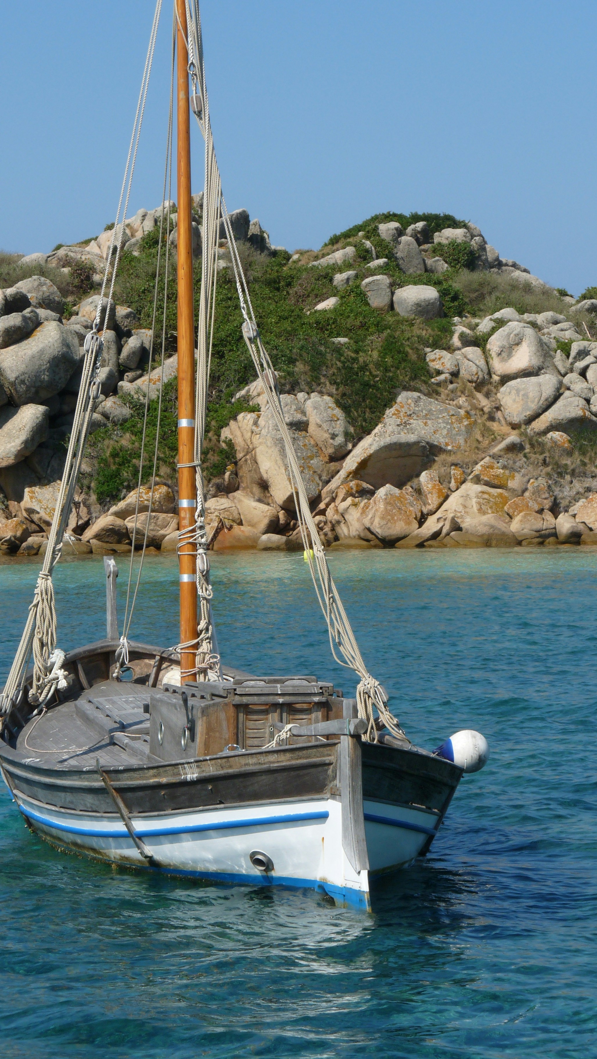 Sailboat at Dawn: A Quiet Harbor with Rocky Backdrop