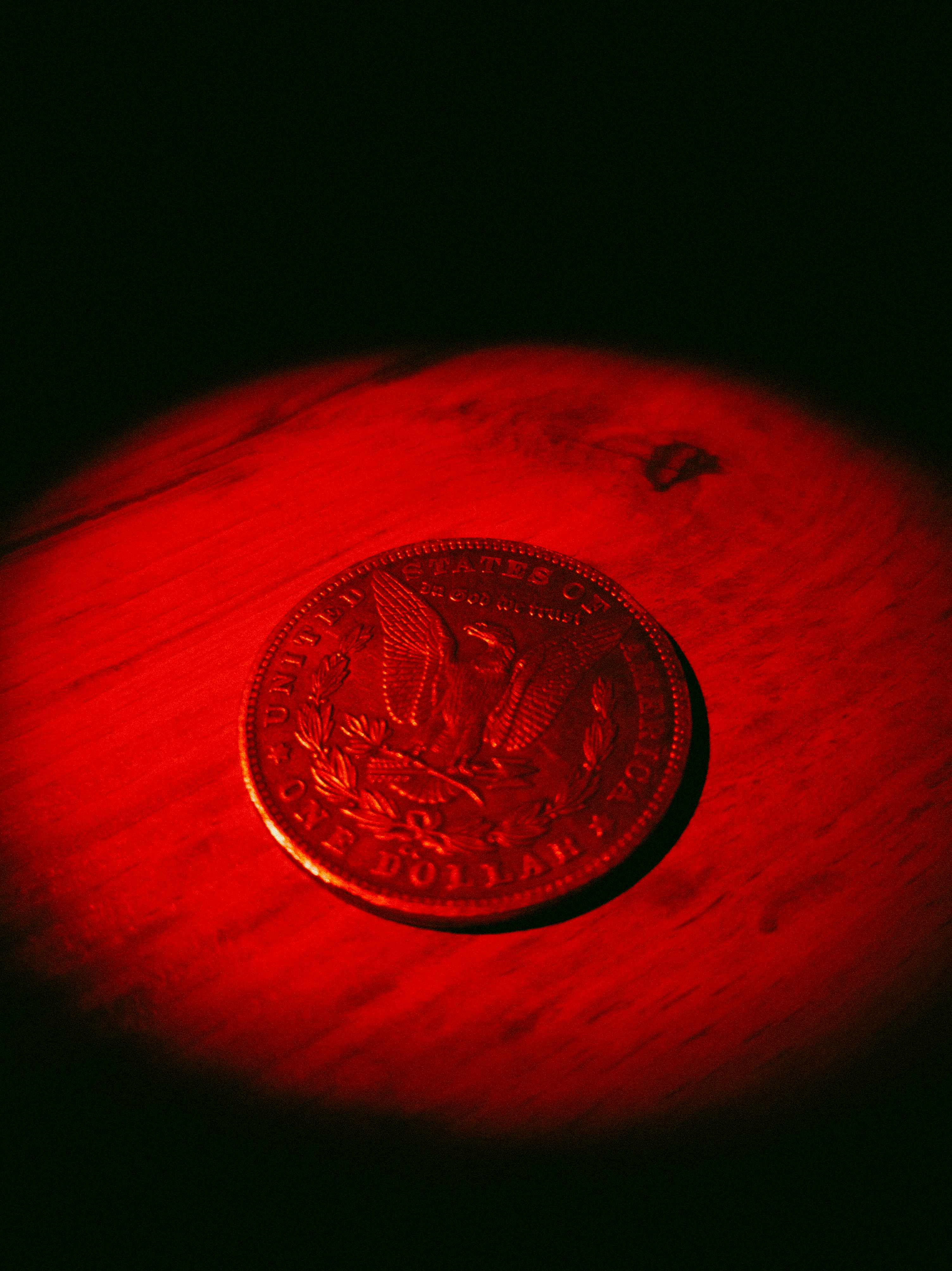 Crimson Spotlight: A single coin under a focused red glow