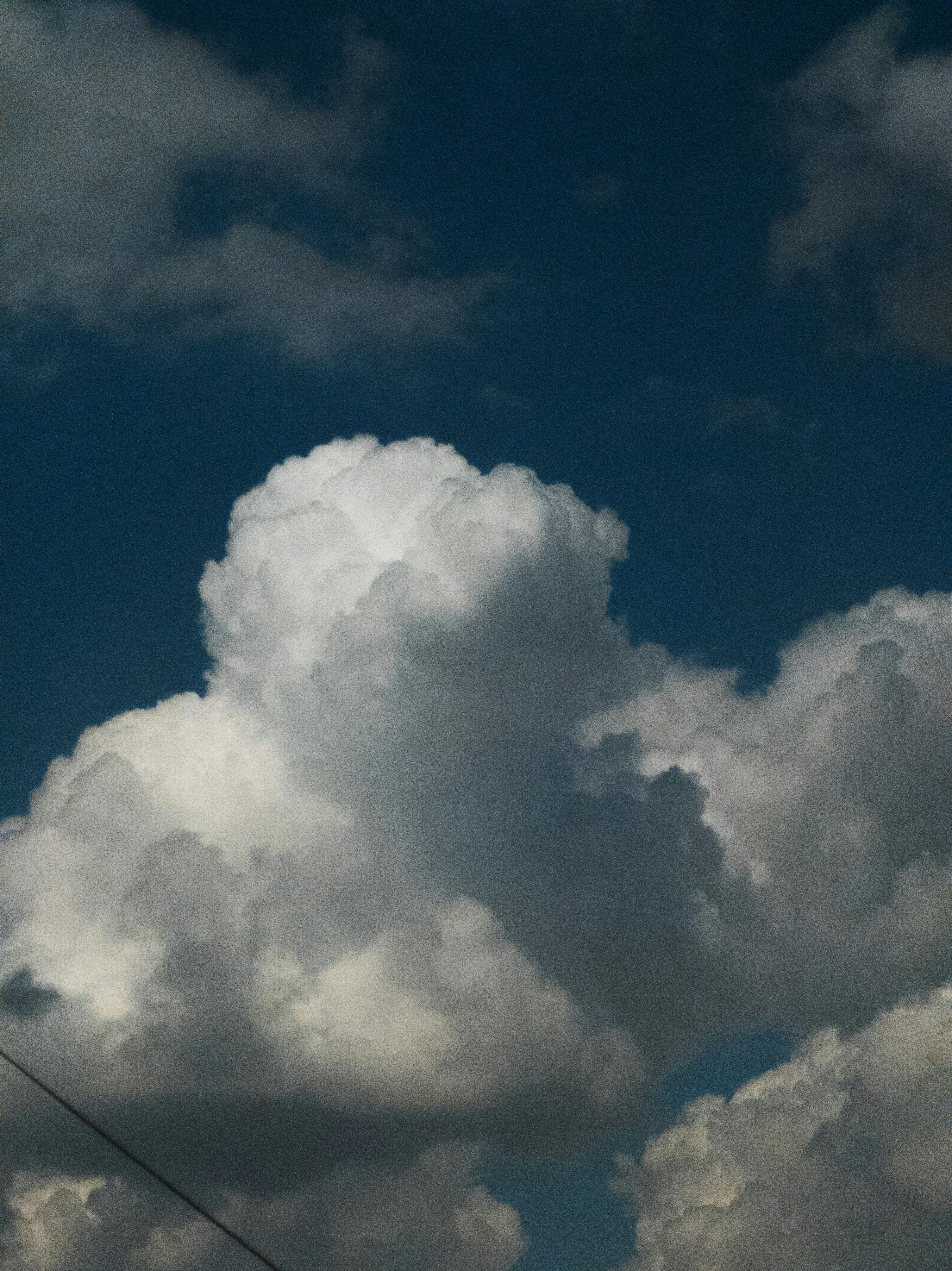 Dramatic cloud formation fills the frame with a deep blue sky backdrop, a high-contrast study of light and shadow.