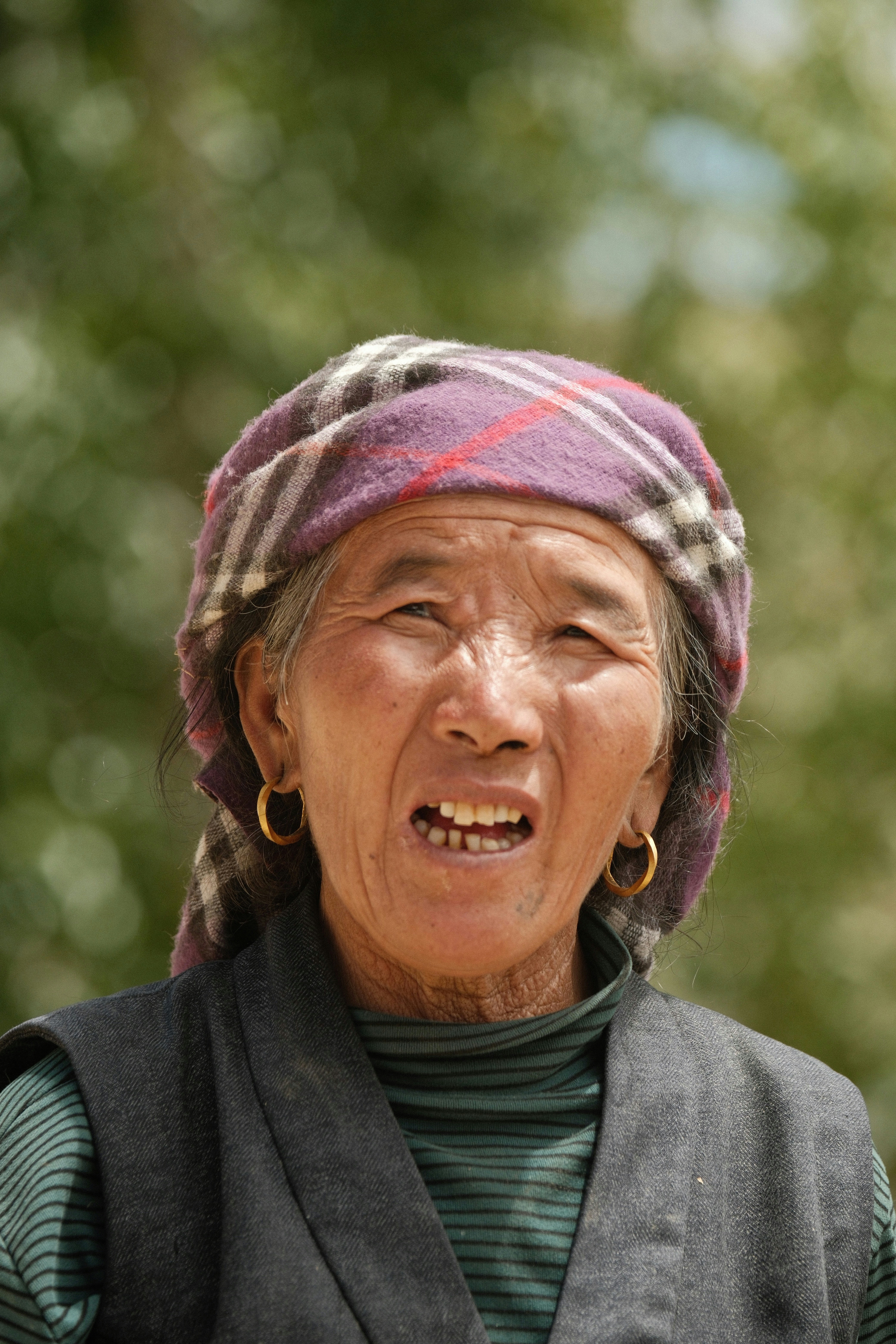 Weathered Wisdom: Elderly woman with headscarf in sunlit outdoor setting