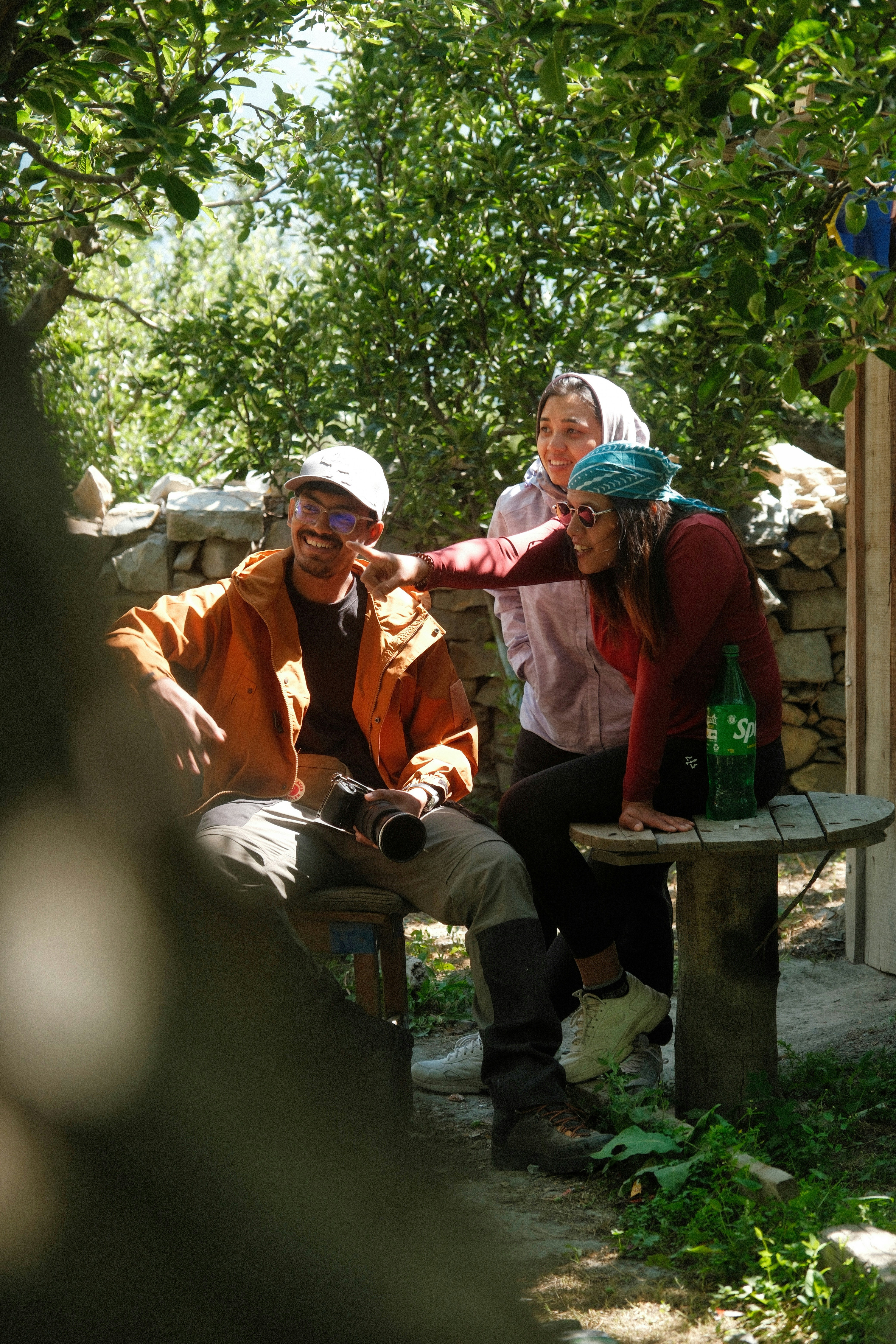 Friends in a sunlit garden sharing a laugh, camera at hand