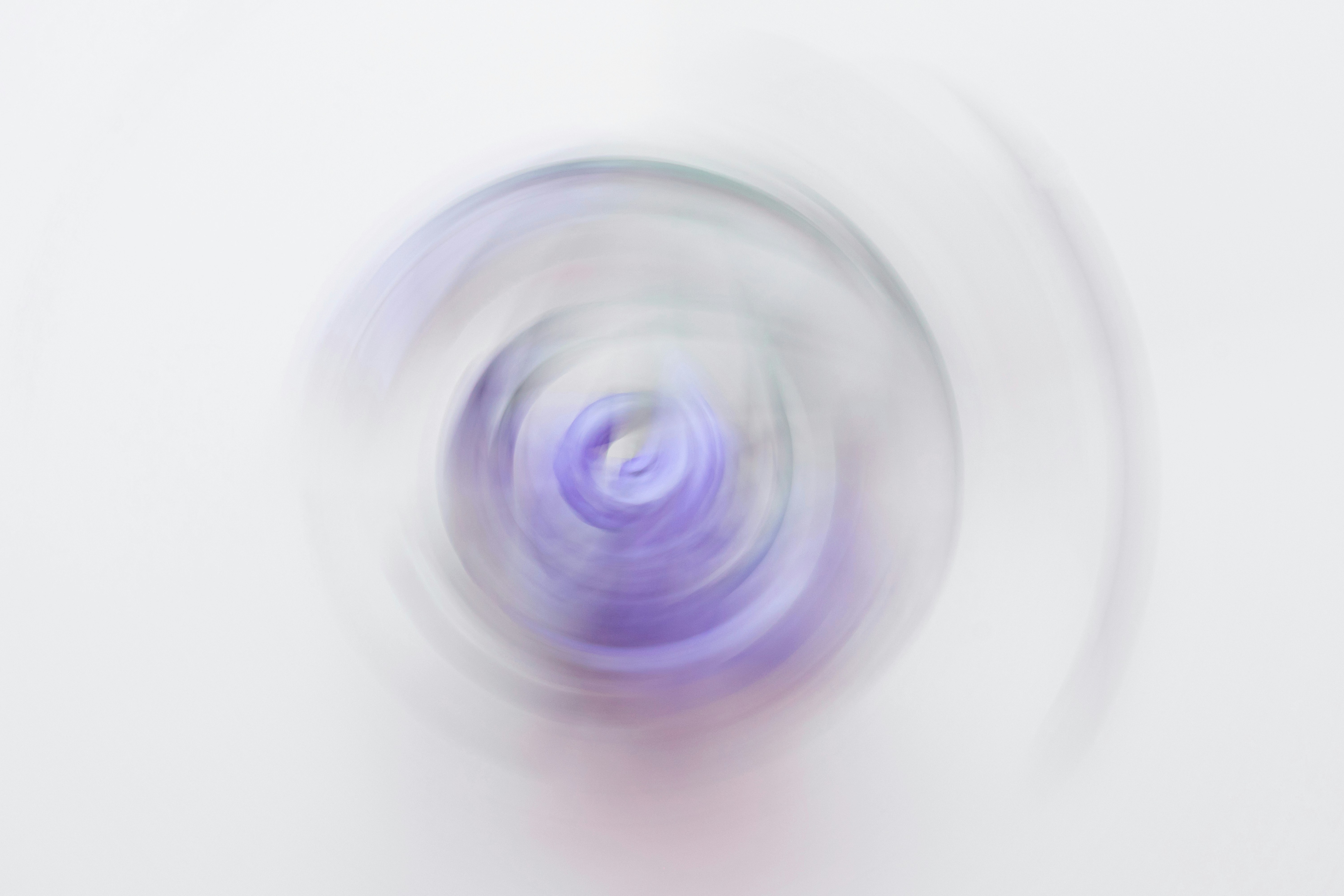 Soft, swirling violet center with radial motion blur on a bright background; an abstract, graphic moment rather than a recognisable subject. Abstract swirl emphasis suitable for art or design context.