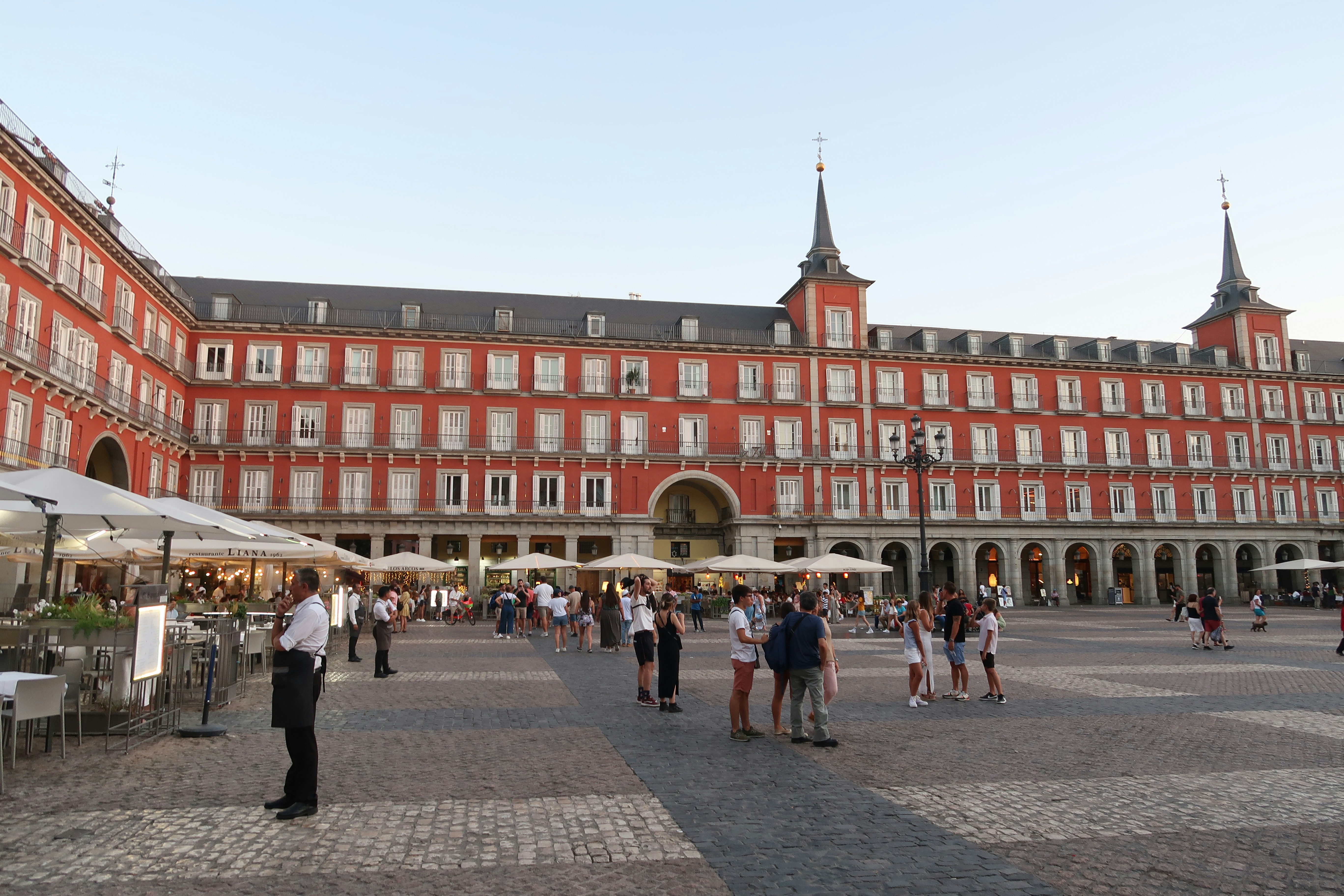 Red-brick Plaza: A Sunlit Arcaded Facade with People at the End