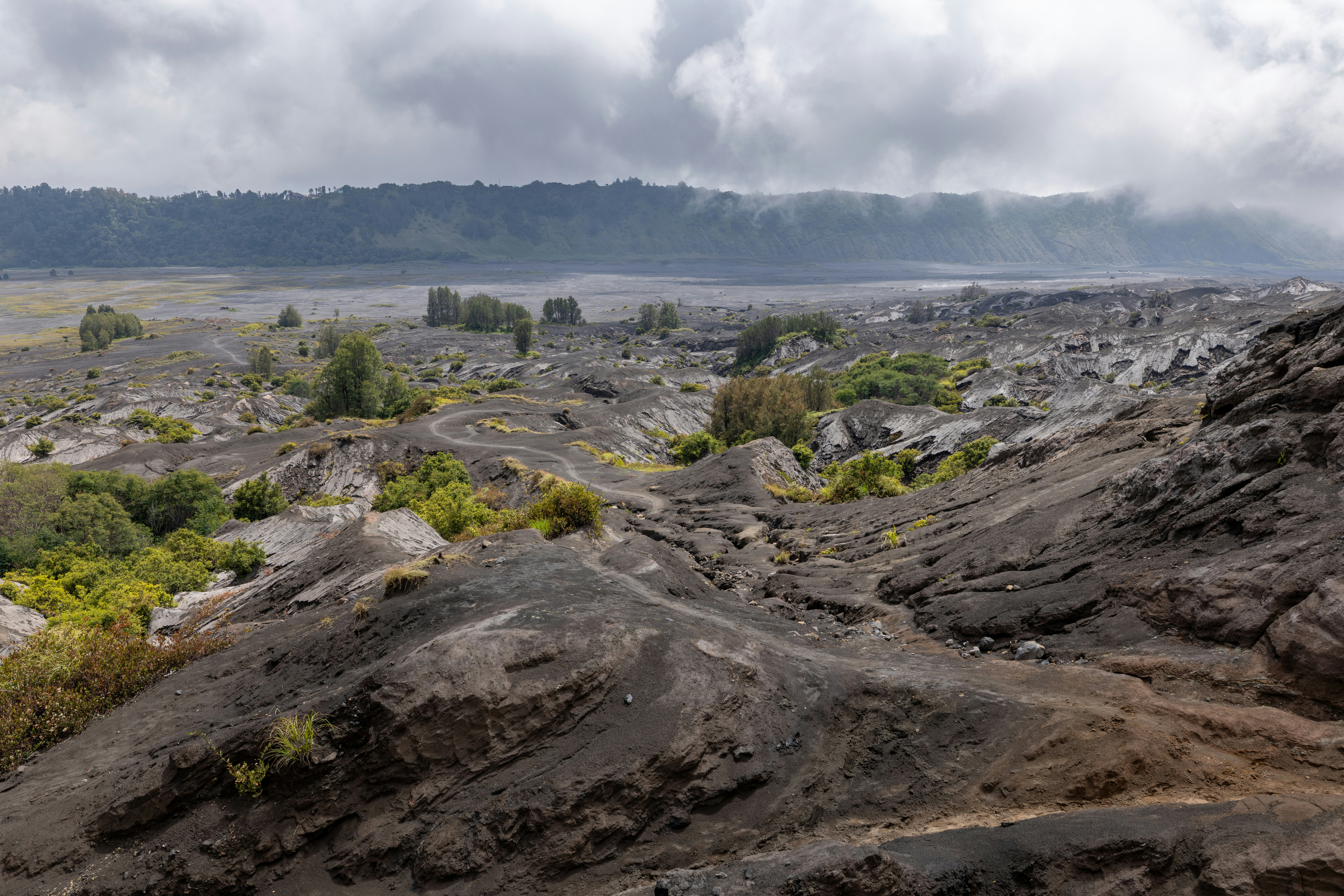 Charred lava fields and distant haze under a brooding sky