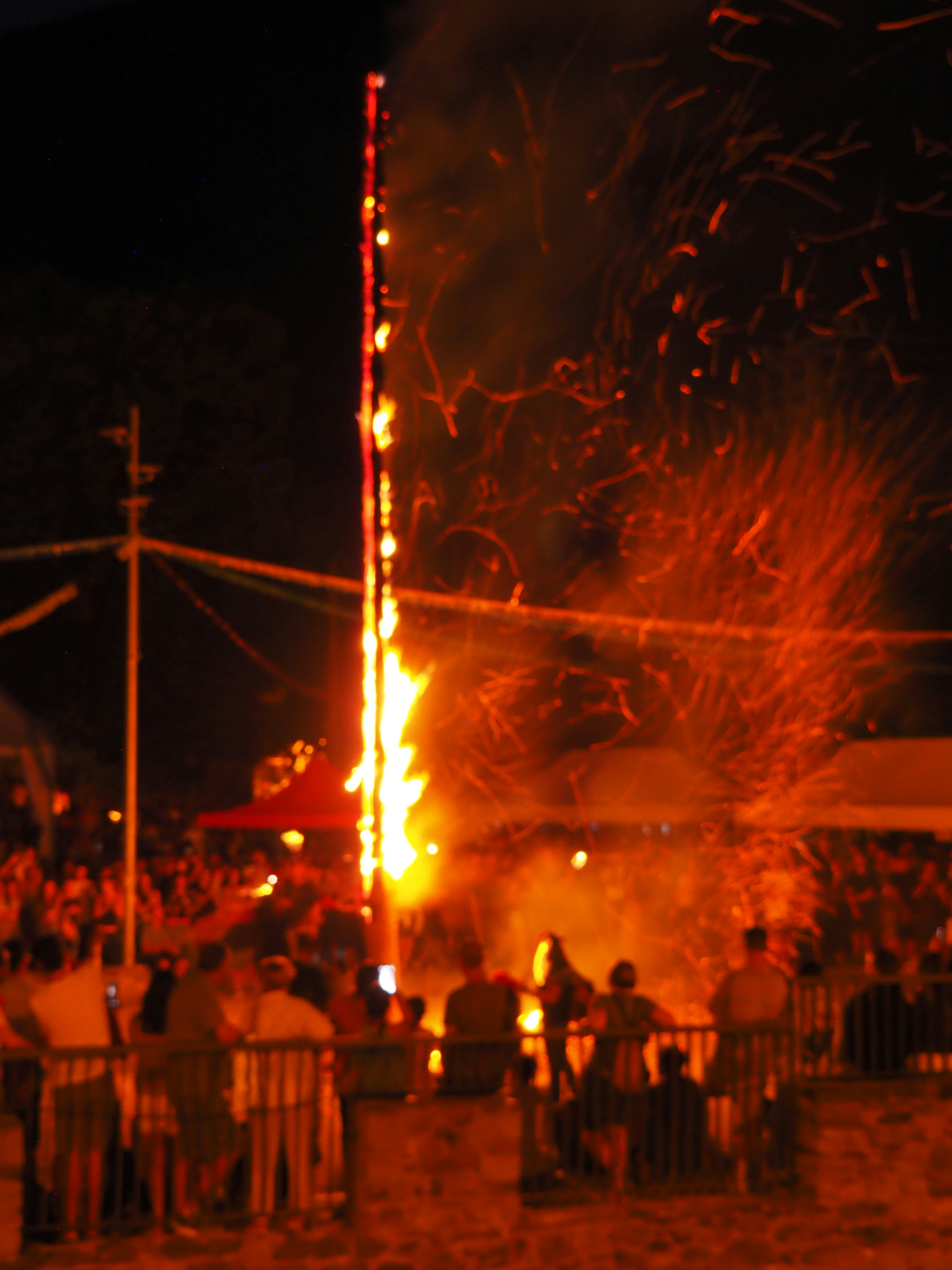 Night Flame: Crowd Gathers Around a Tall Ignited Structure