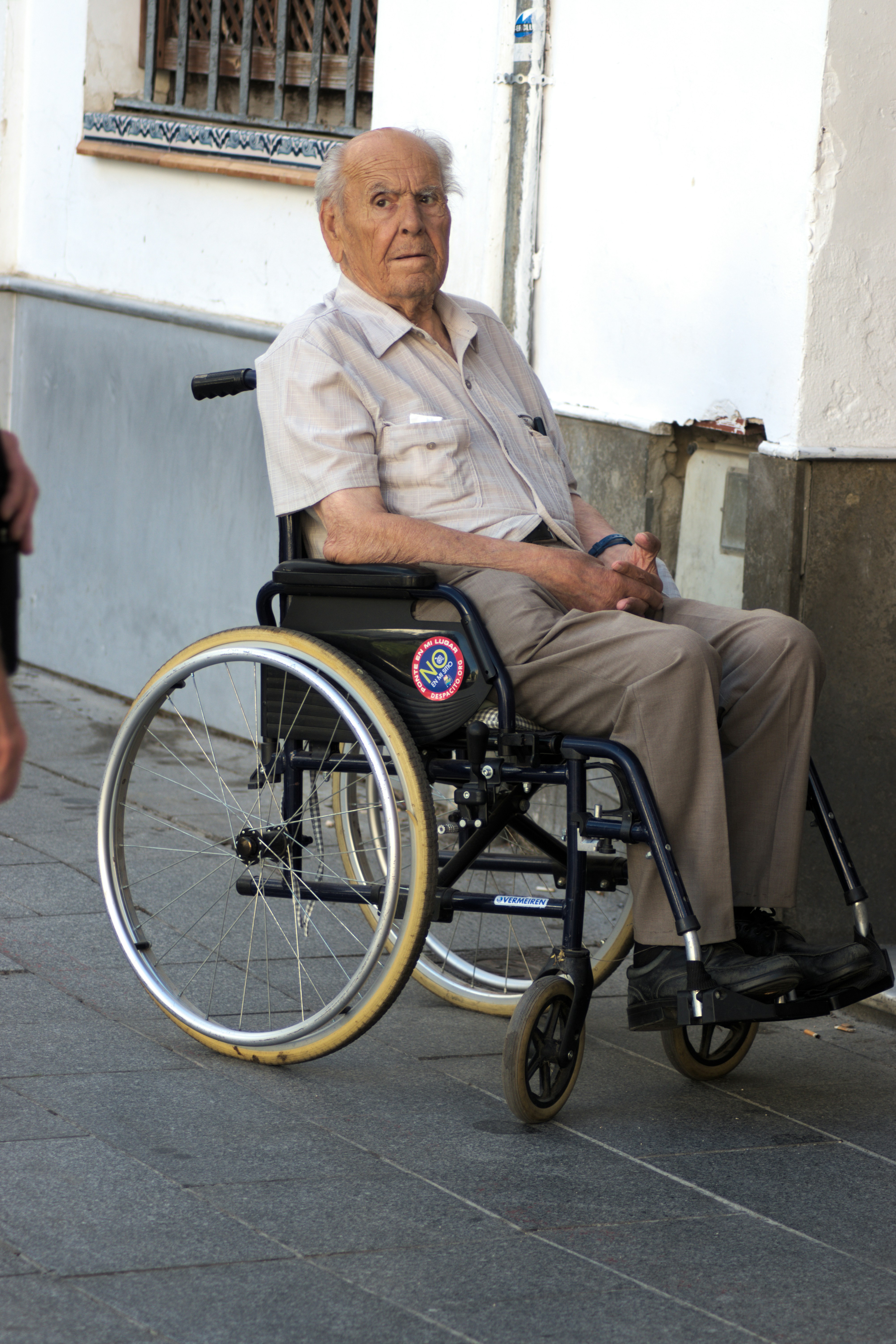 A Quiet Moment: An Elderly Man in a Wheelchair on a City Street