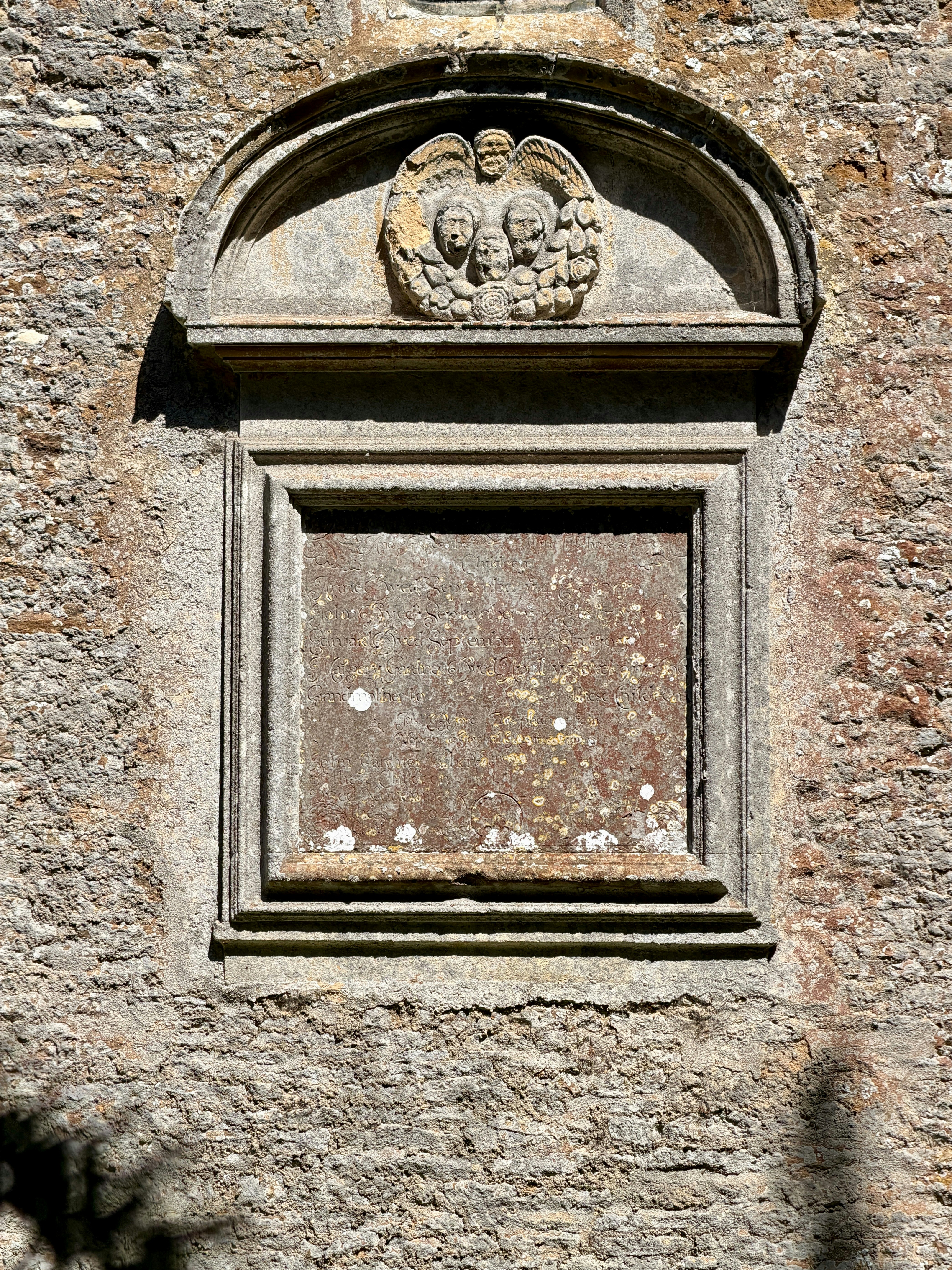 Sunlit Niche: A Weathered Stone Window Frieze Above an Empty Panel