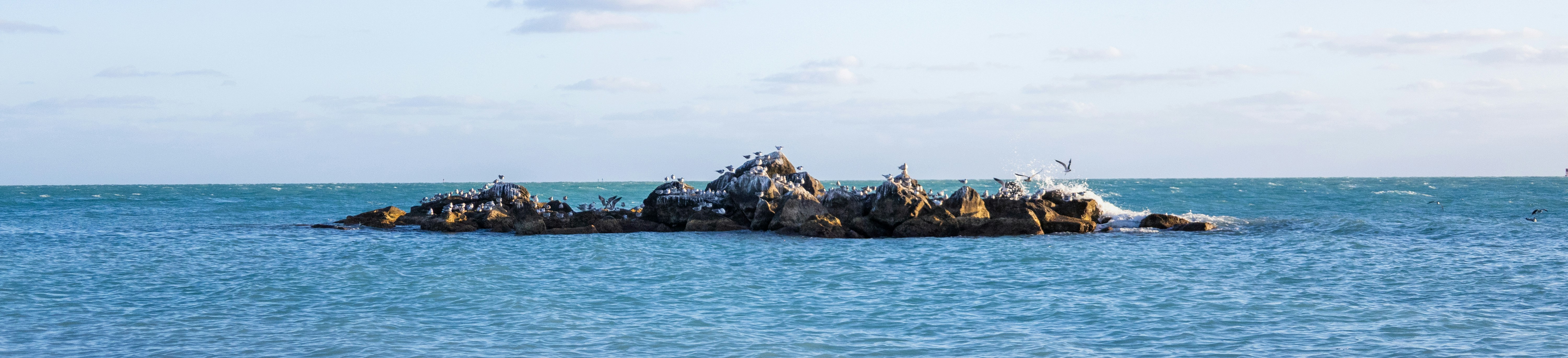 Isolated Break in Blue: A Quiet Rock Cluster at Sea