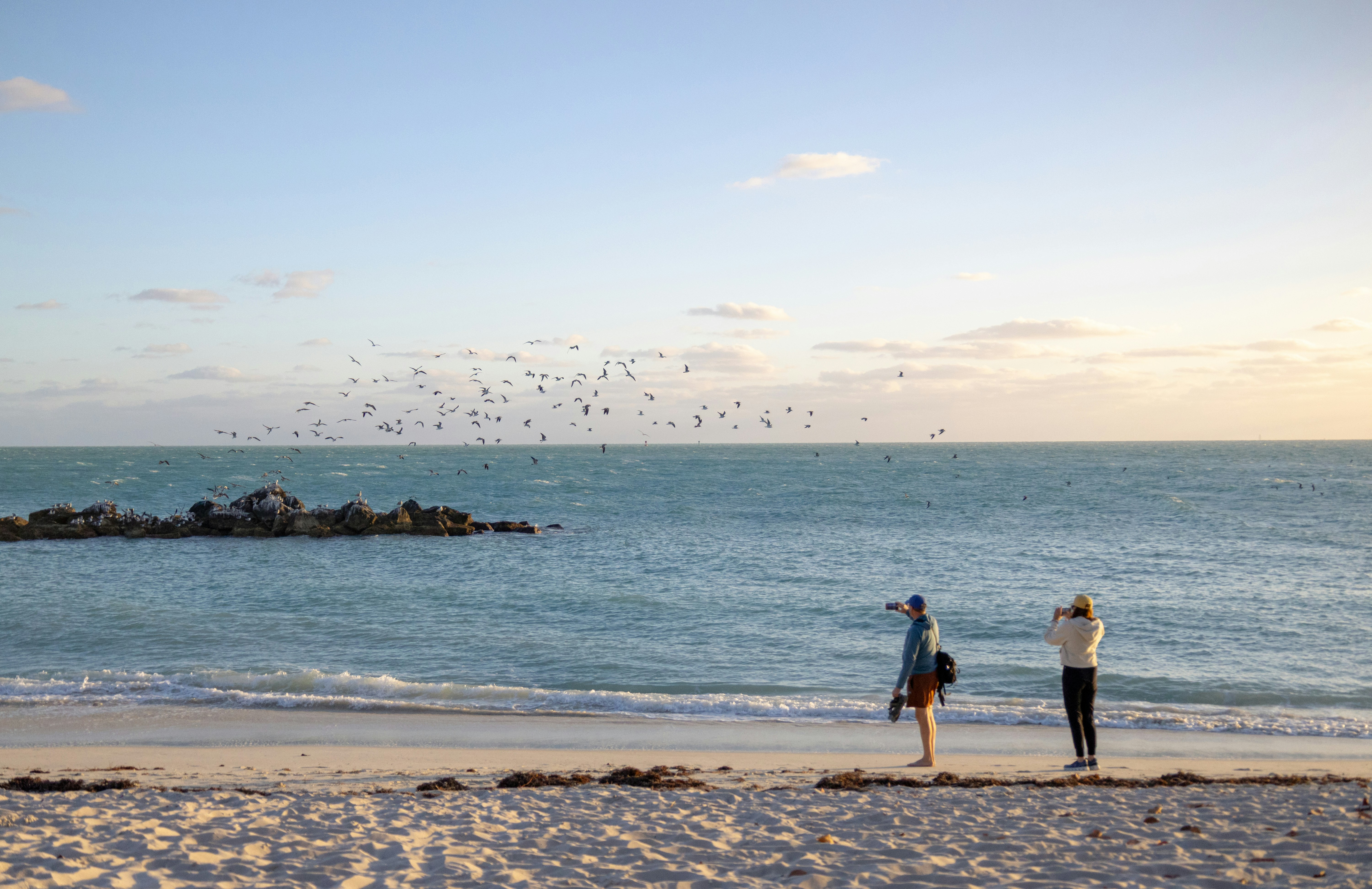 Two Figures on a Quiet Seaside: A Moment Between Shore and Sky