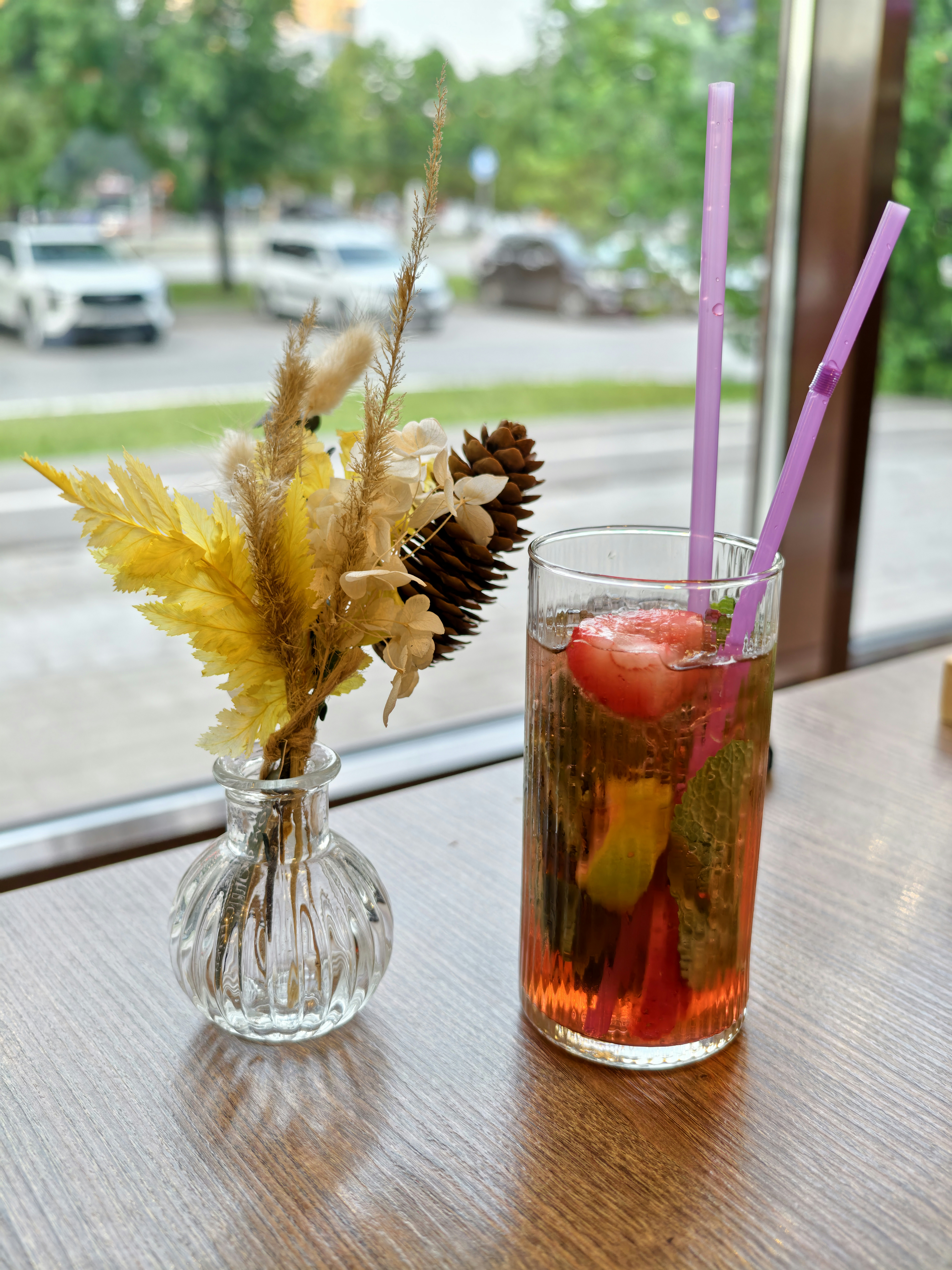 Refreshing strawberry drink with dried flowers on a wooden table.