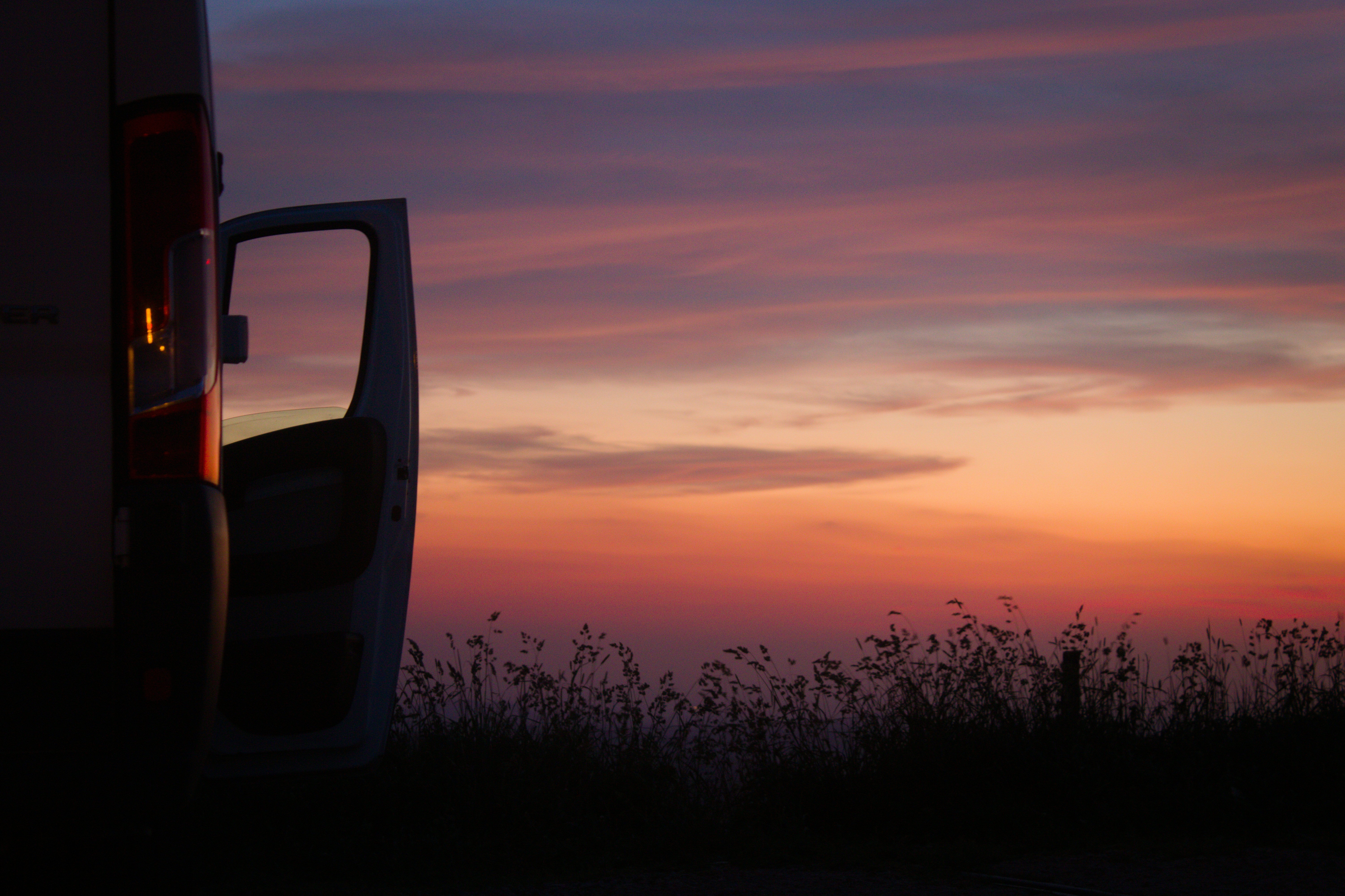 Dusk Retreat: Van Door Open Over a Quiet Horizon