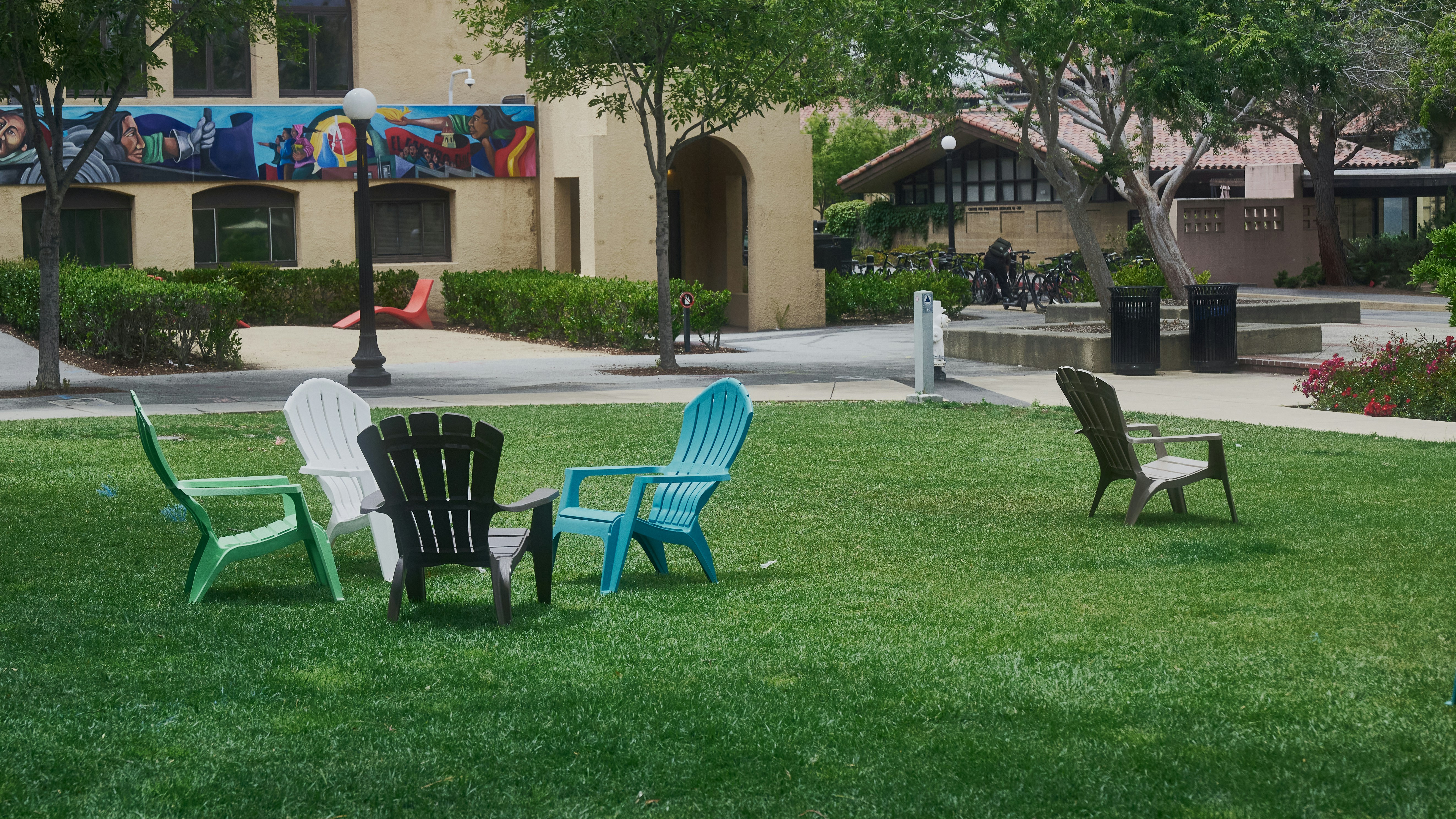 Colorful adirondack chairs on green grass near buildings.