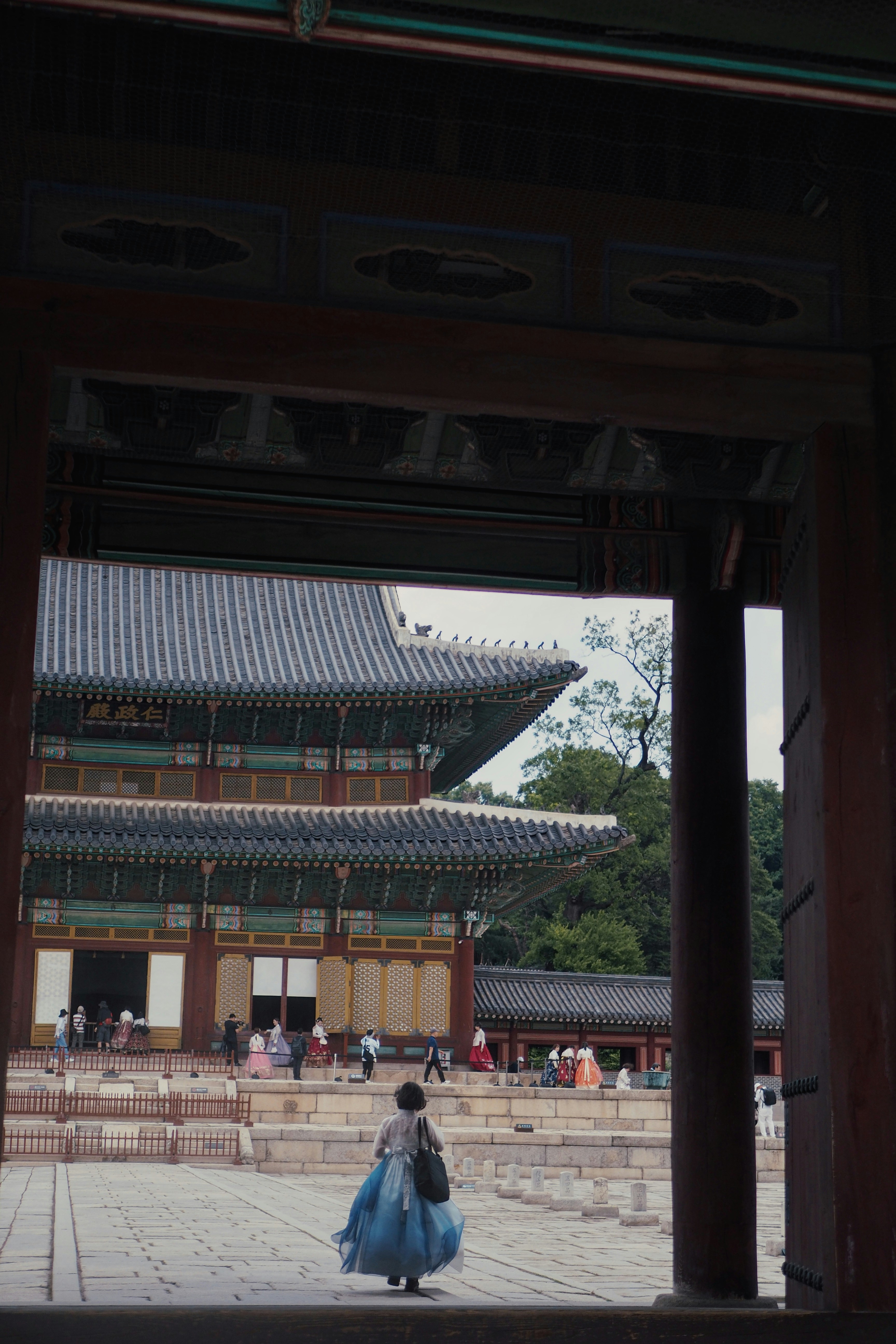 Blue-skirted traveler stepping through a temple gateway