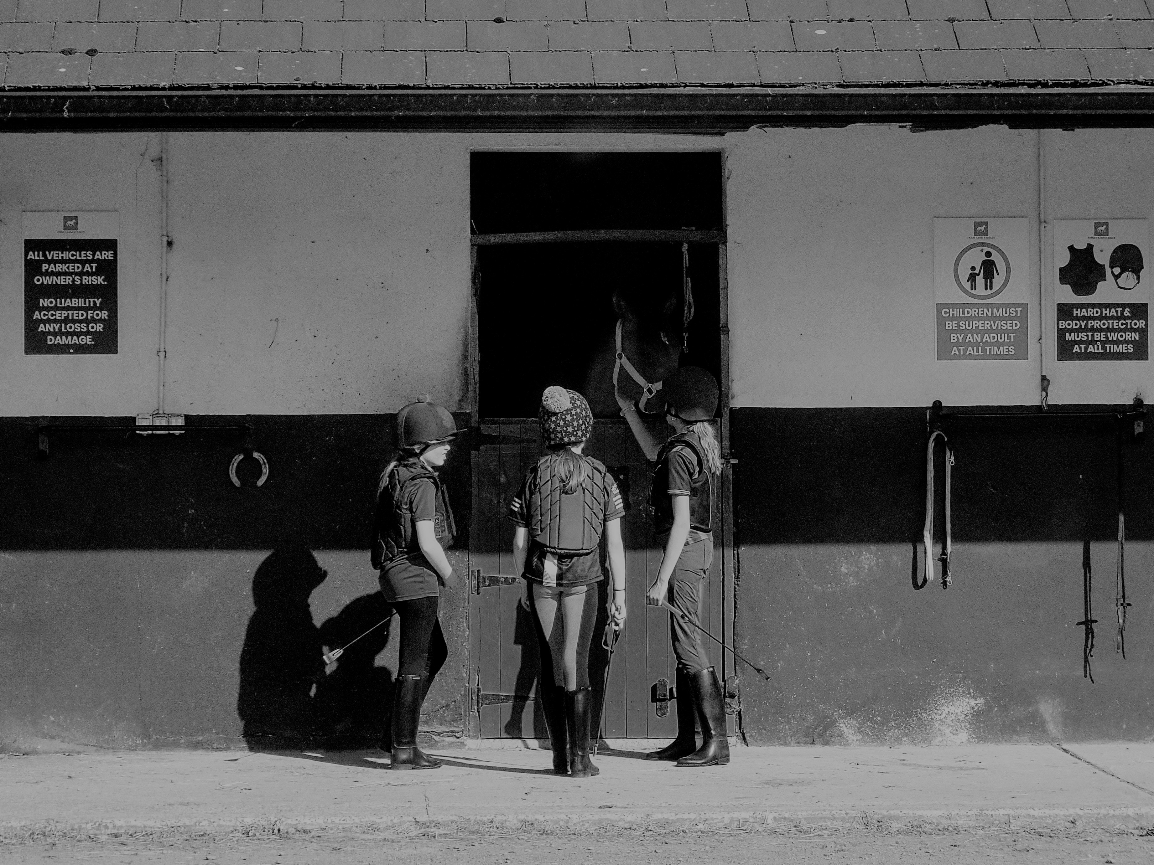 Black-and-white scene of armed soldiers gathered at a doorway of a utilitarian building, silhouettes and gear emphasized. This is a documentary-style photograph likely capturing a brief moment of briefing outside a facility.