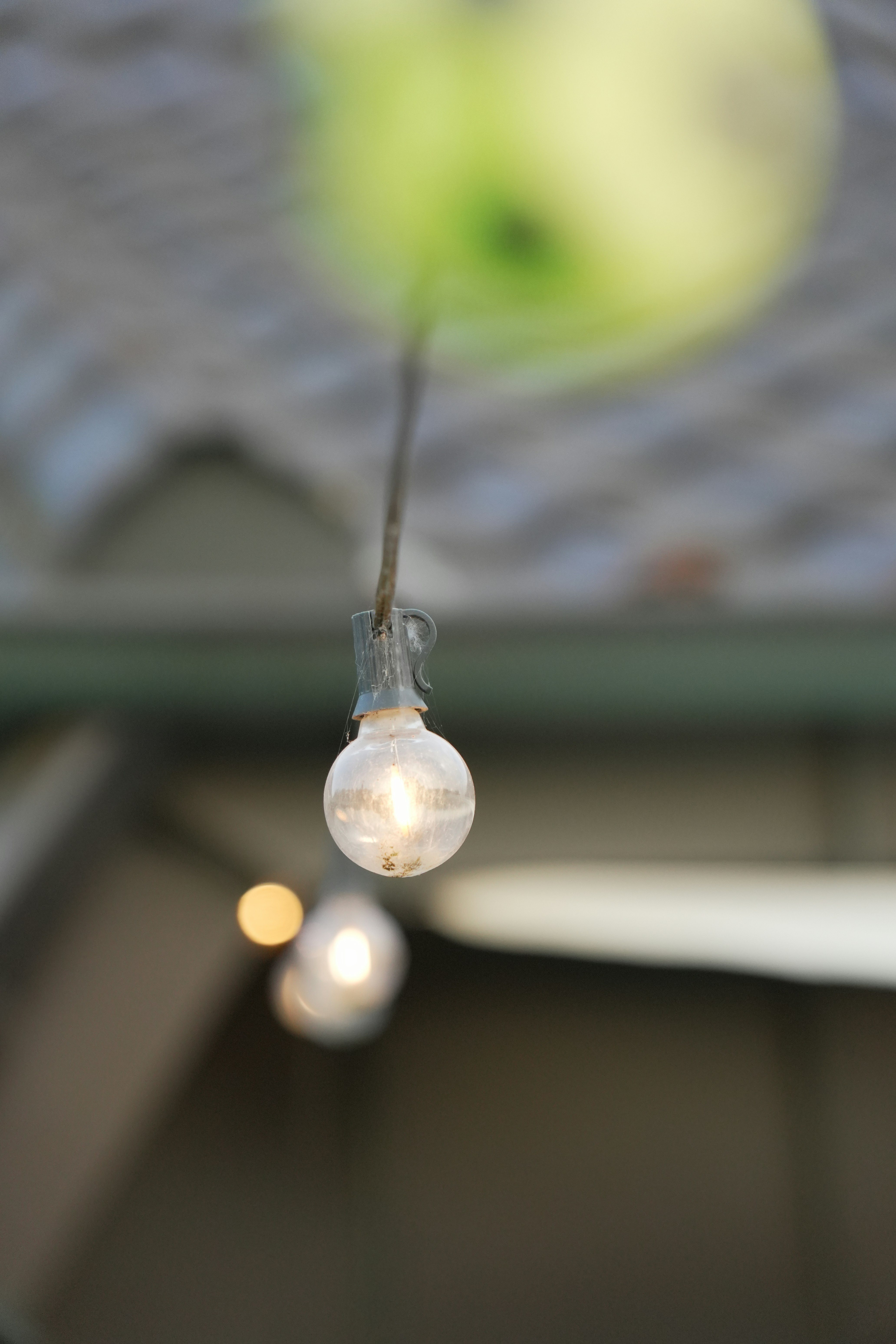Dangling Bulb Beneath Blurred String Lights