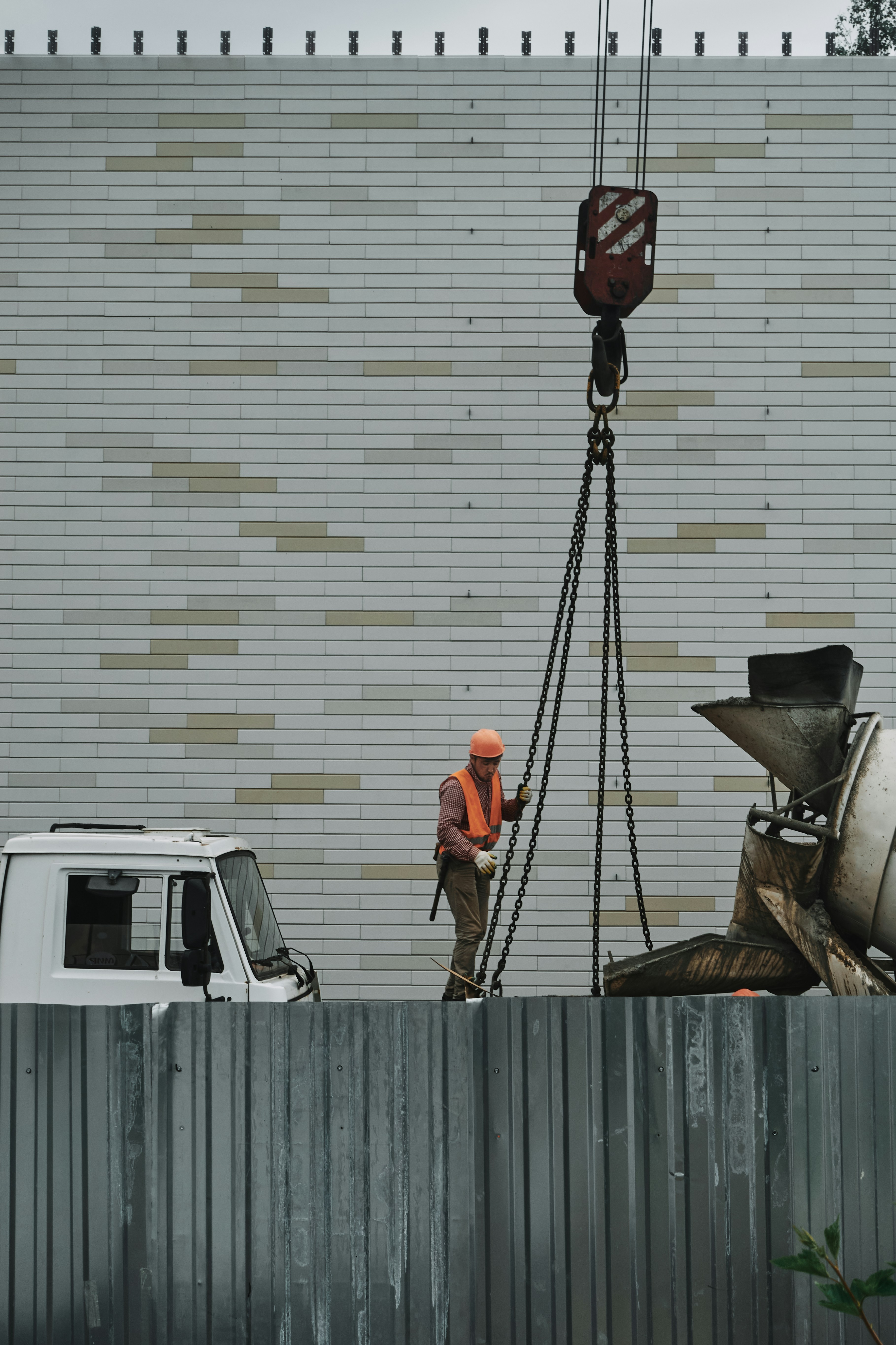 Cranes, Chains, and Construction: A Worker in Profile on a Dimmed Site