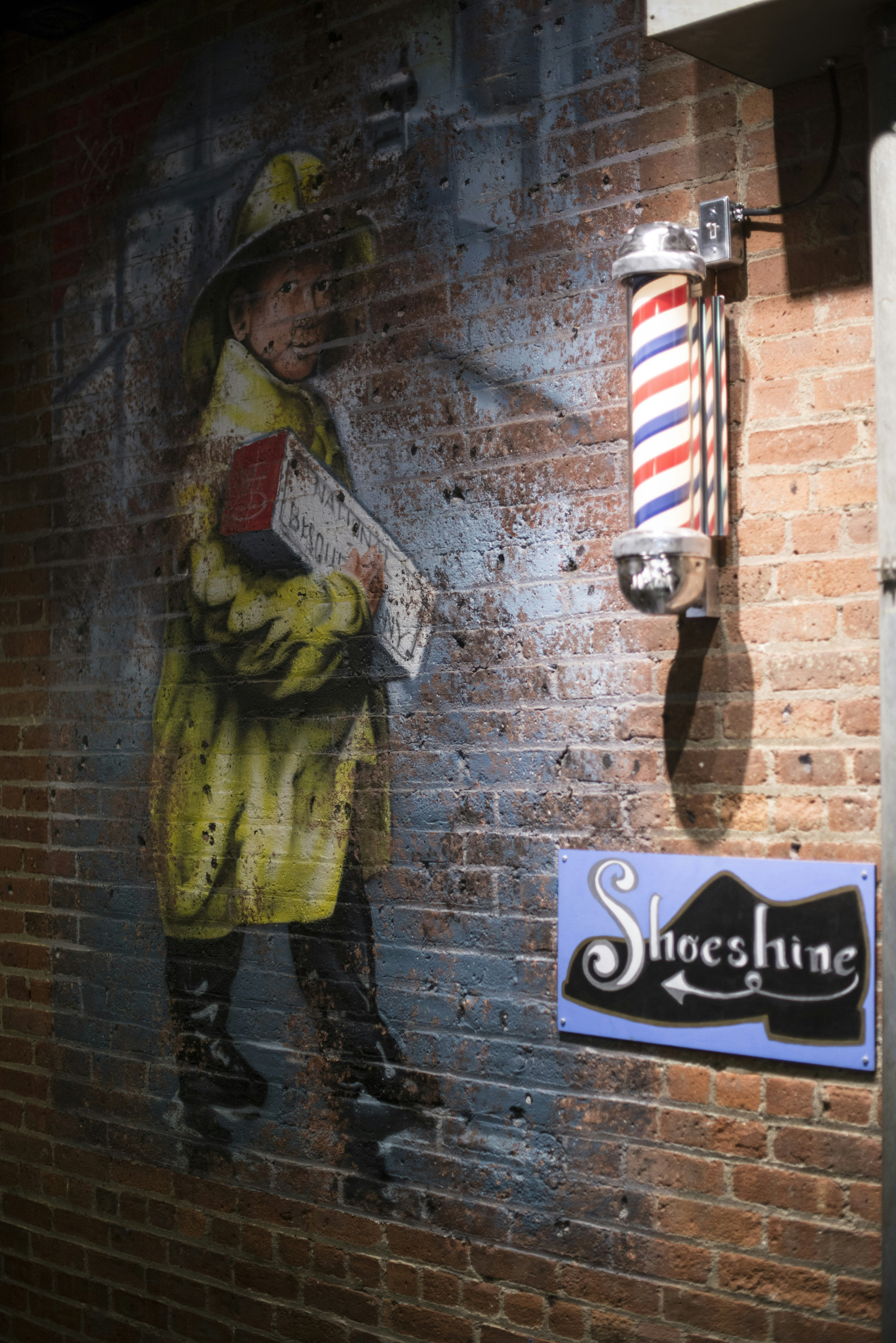 Brick-Worn Messenger: A Firefighter mural beside a striped barber pole