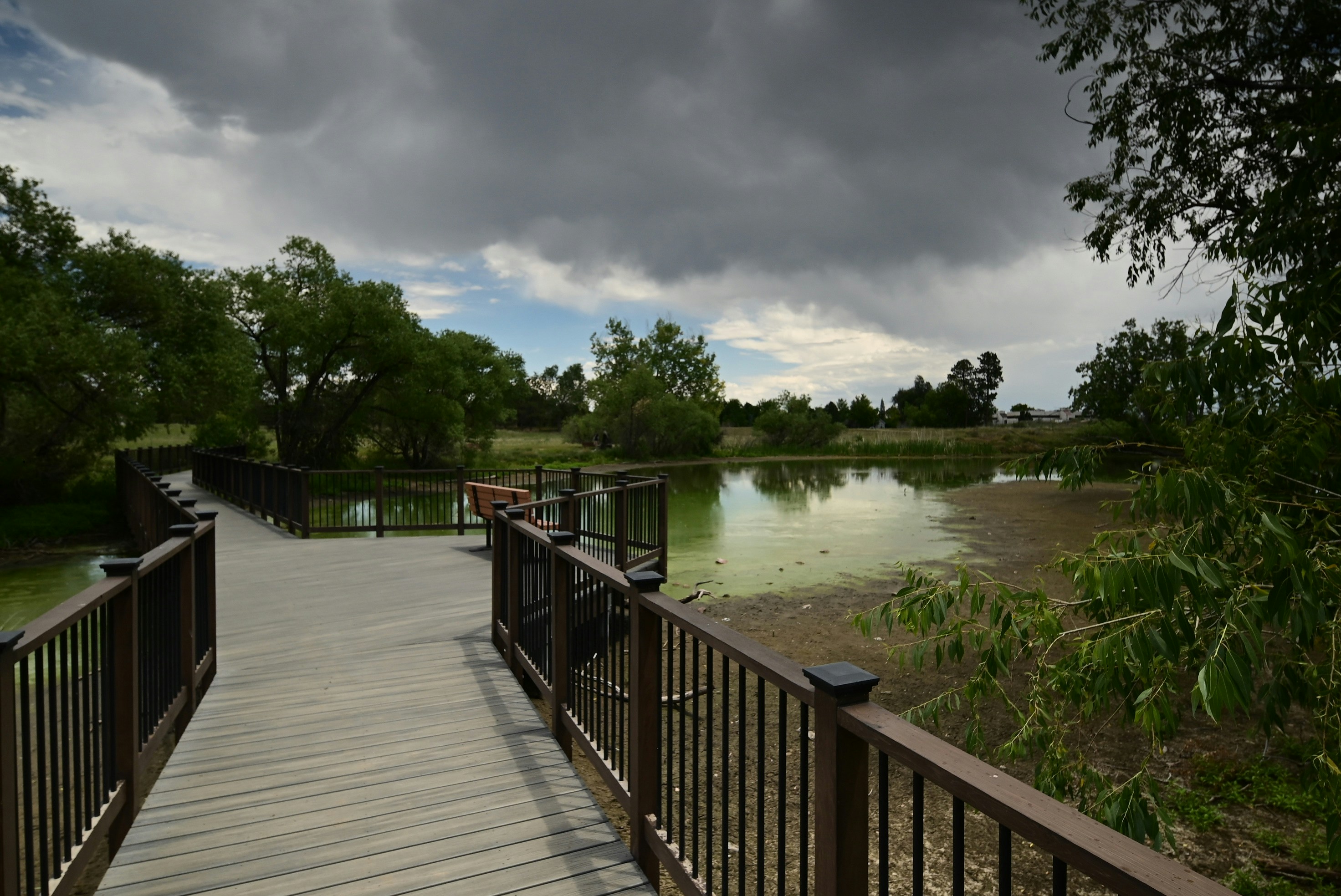 Boardwalk Through a Riverside Park under a Stormy Sky