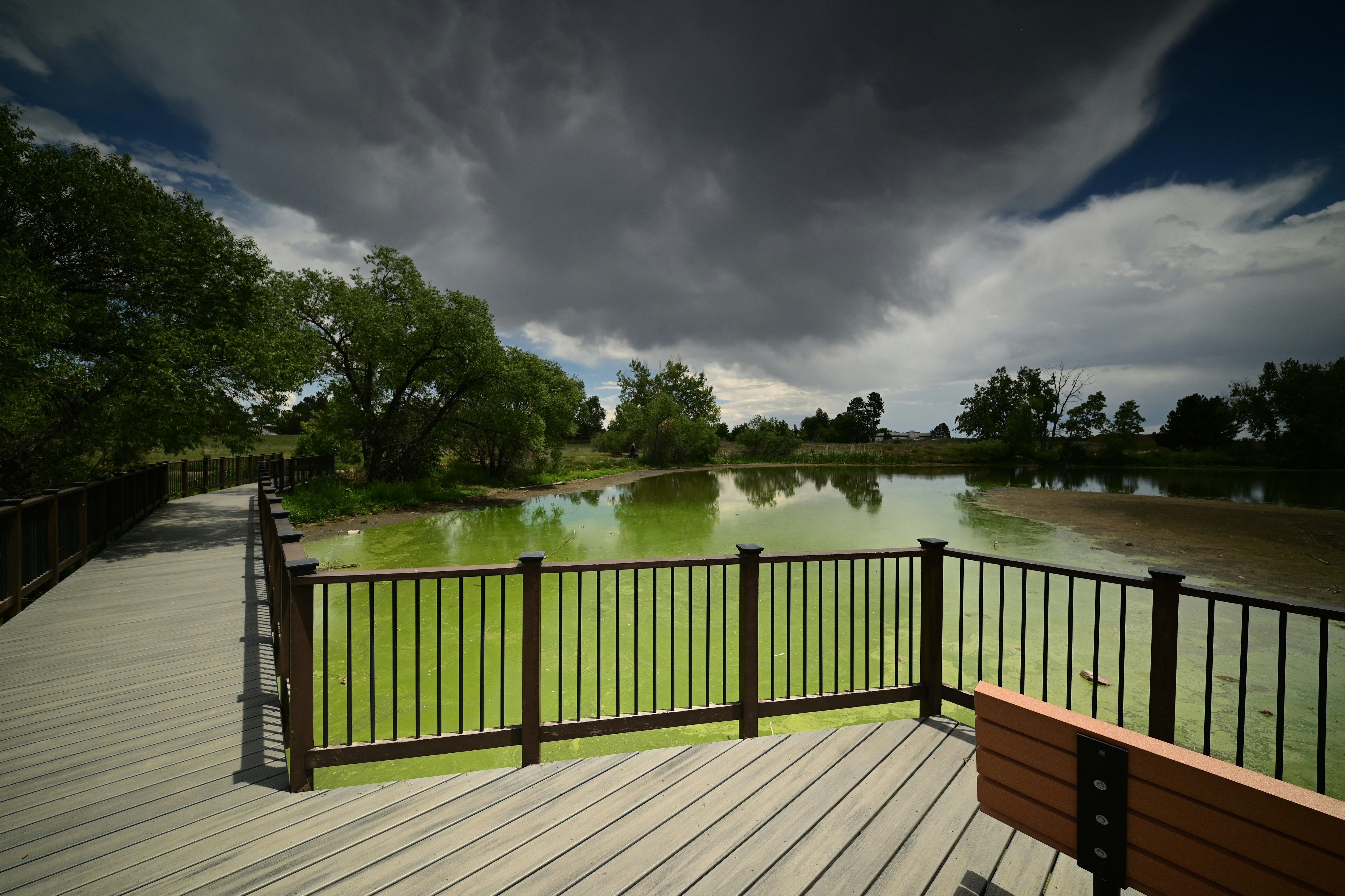 Wooden Deck Framing a Serene Pond Under Dramatic Clouds