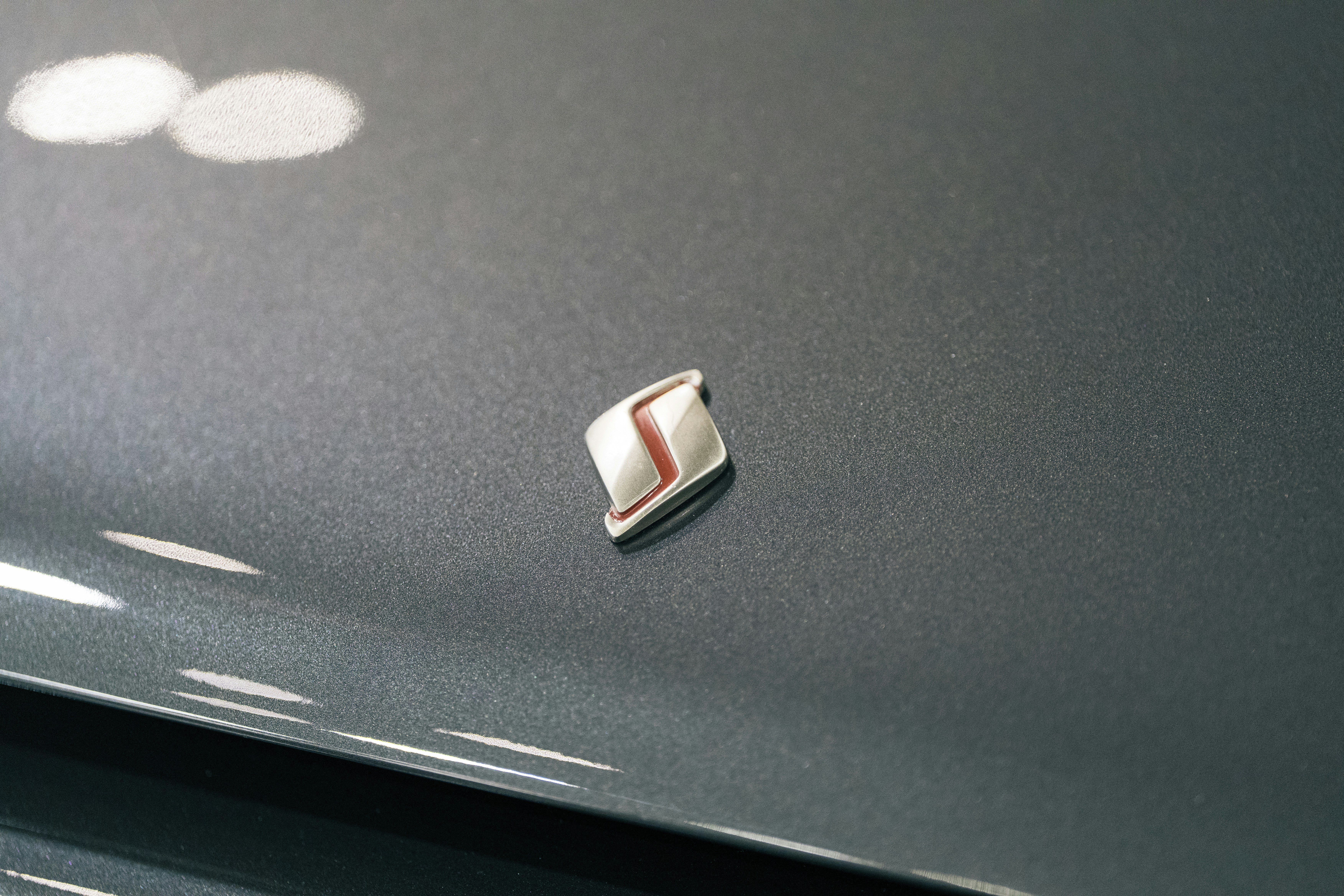 Emblem in Focus: Close-Up of a Car Crest on Metallic Grey Surface