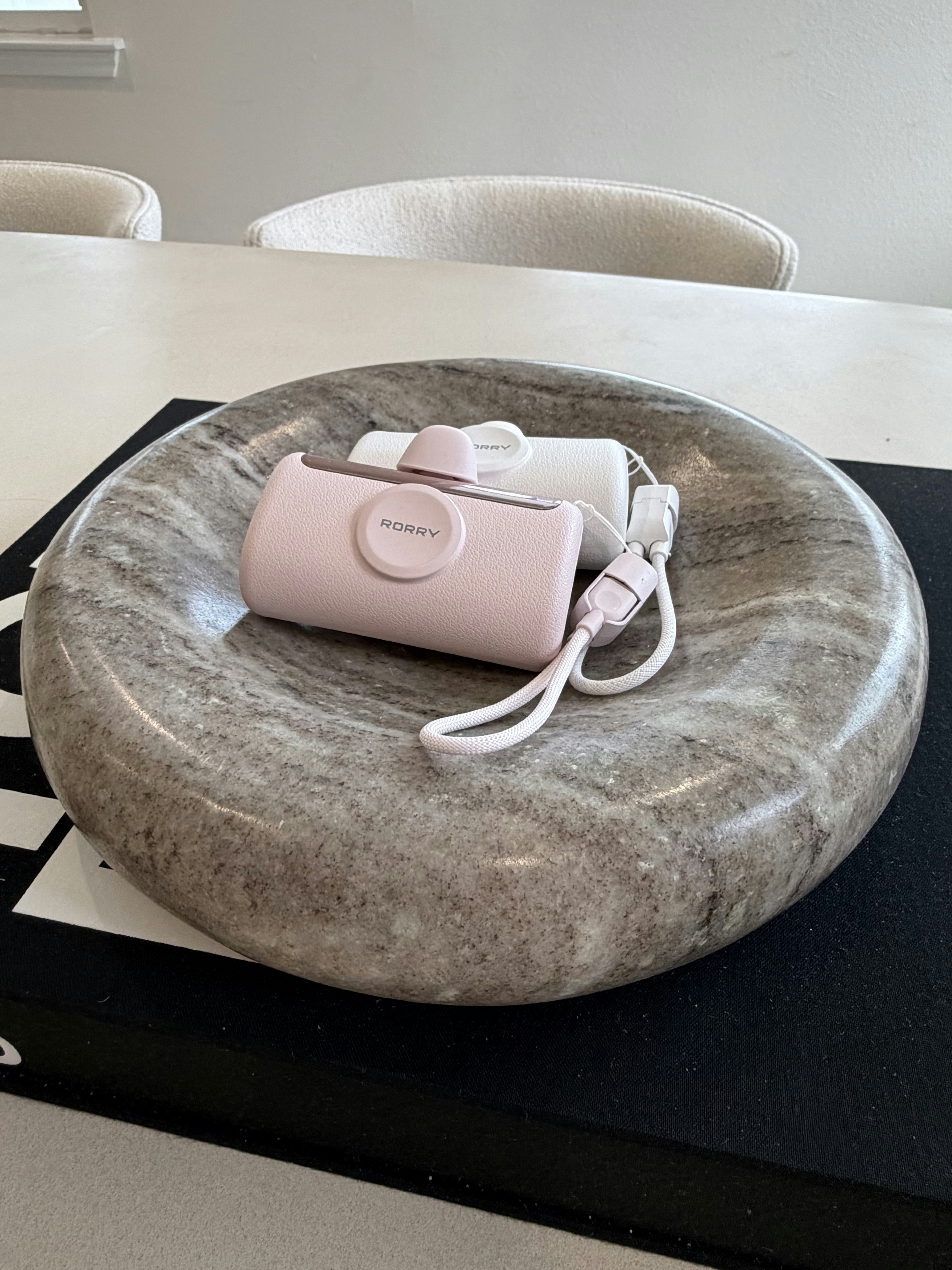 Soft-pink camera pouch resting on a rounded stone centerpiece