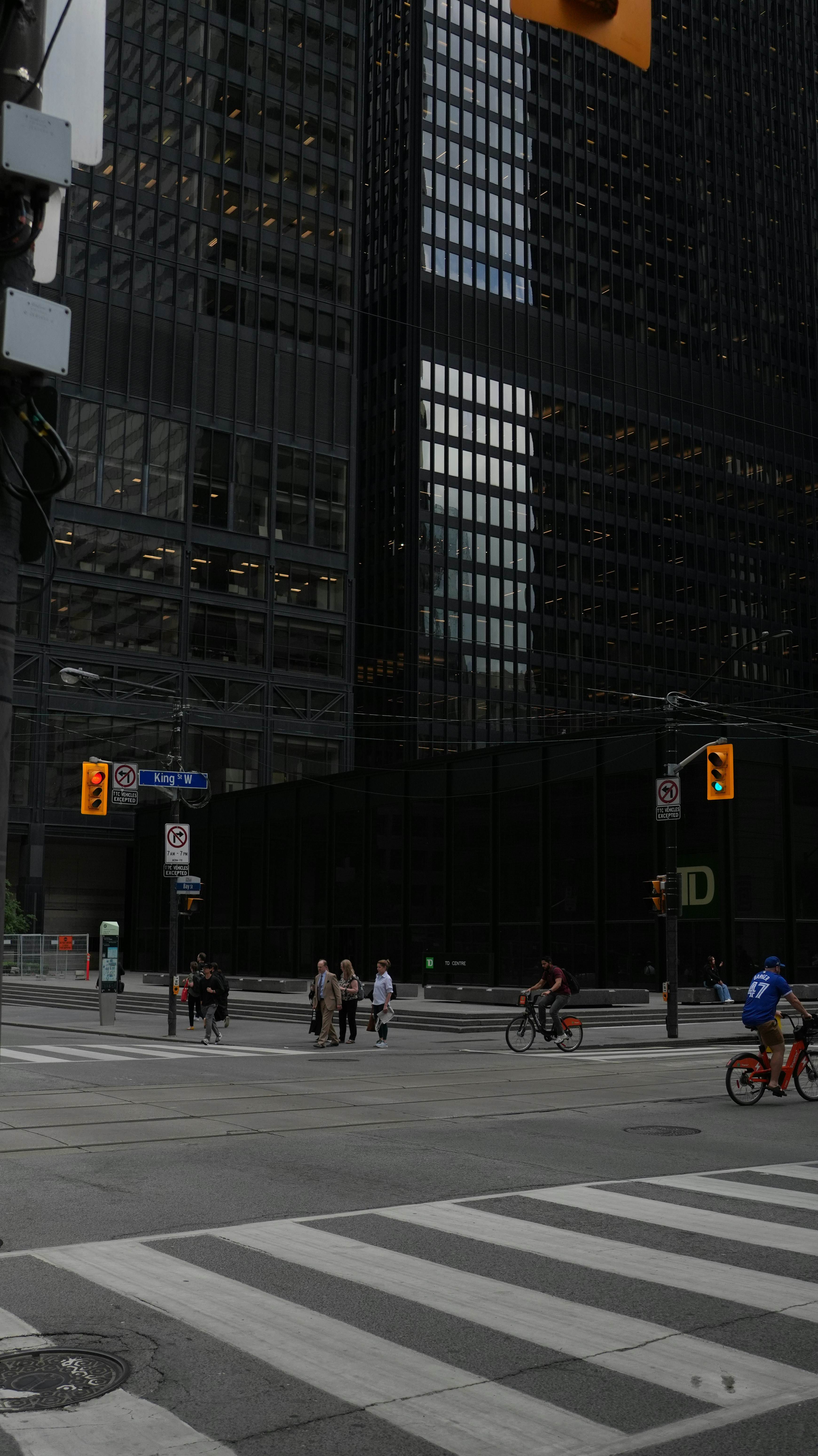 Urban Crossroads: Pedestrians and Cyclists Before a Glass-Flaced Tower