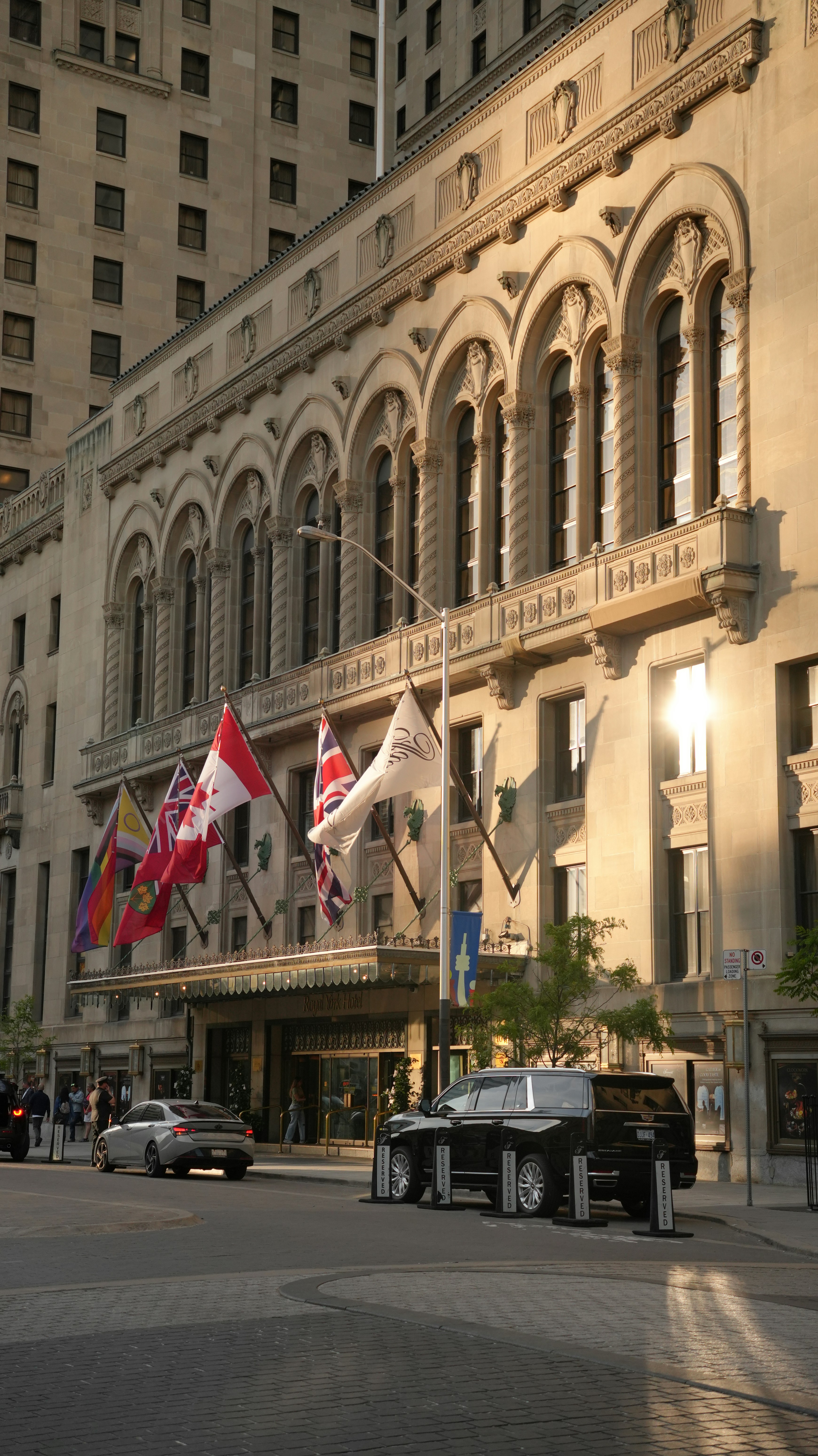 Flags along a grand urban facade bathed in late-afternoon light