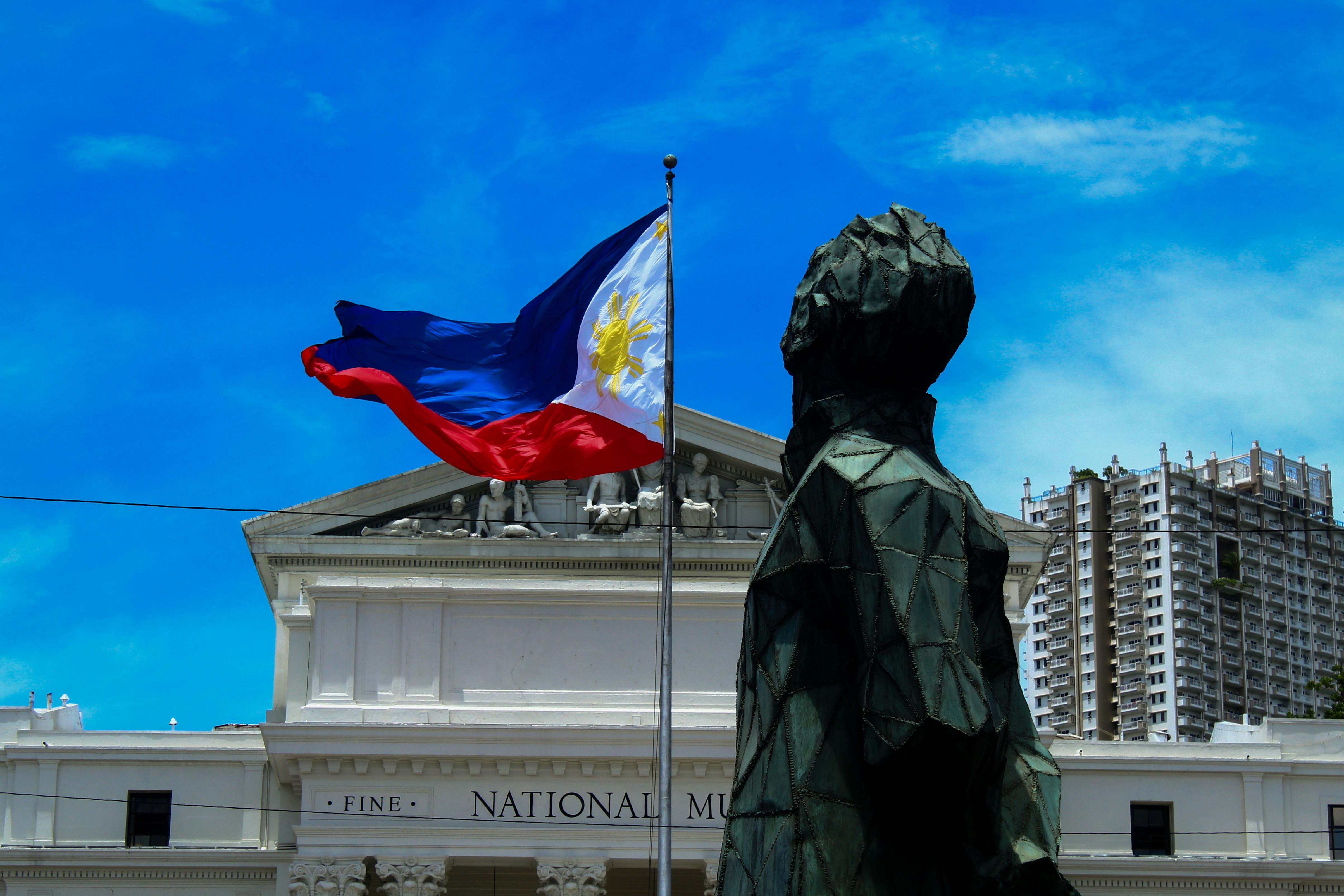 Flag over the National Museum: a quiet hero beside the sculpted figure