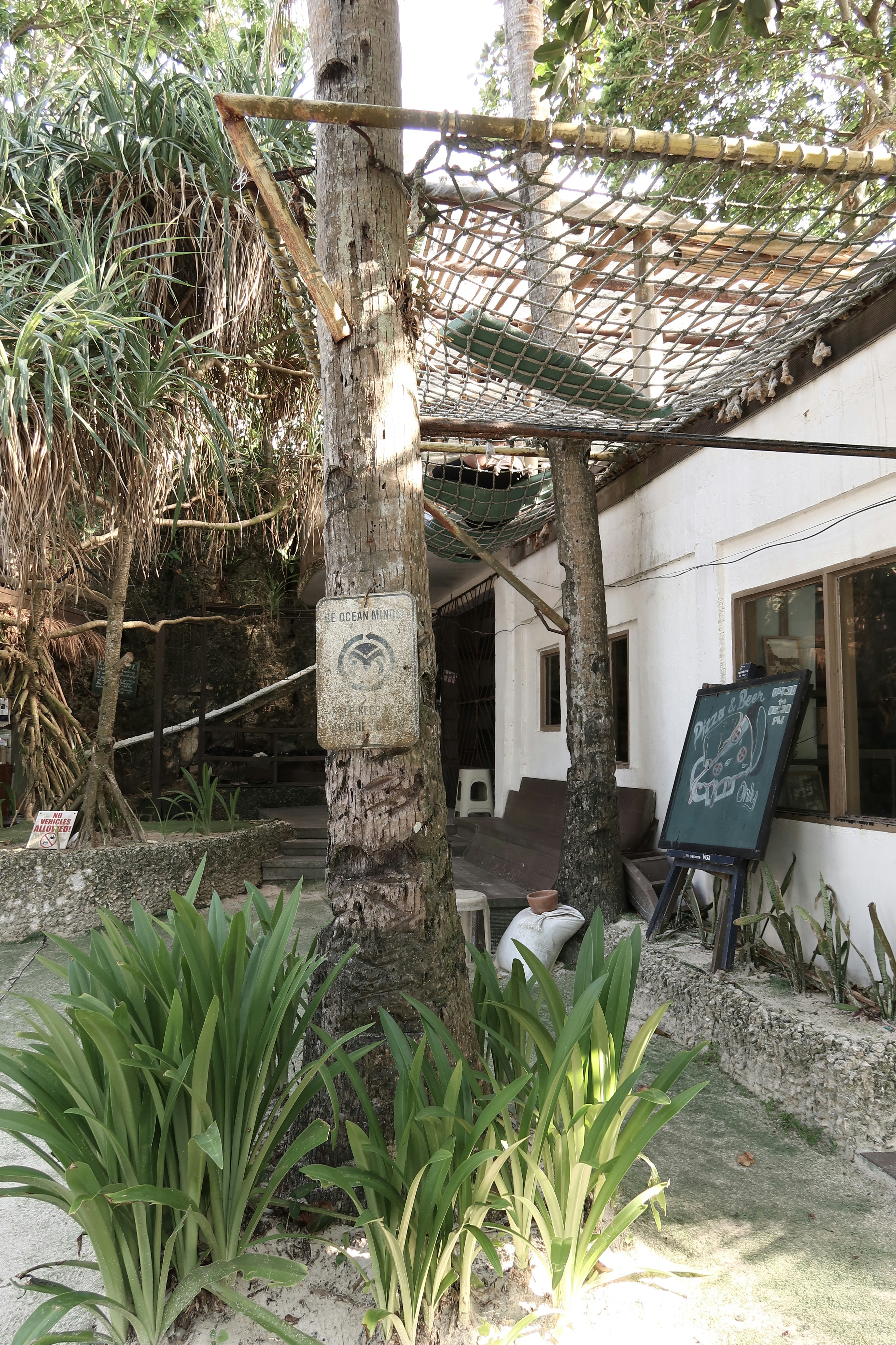 Shady courtyard cafe with a hanging hammock and signpost