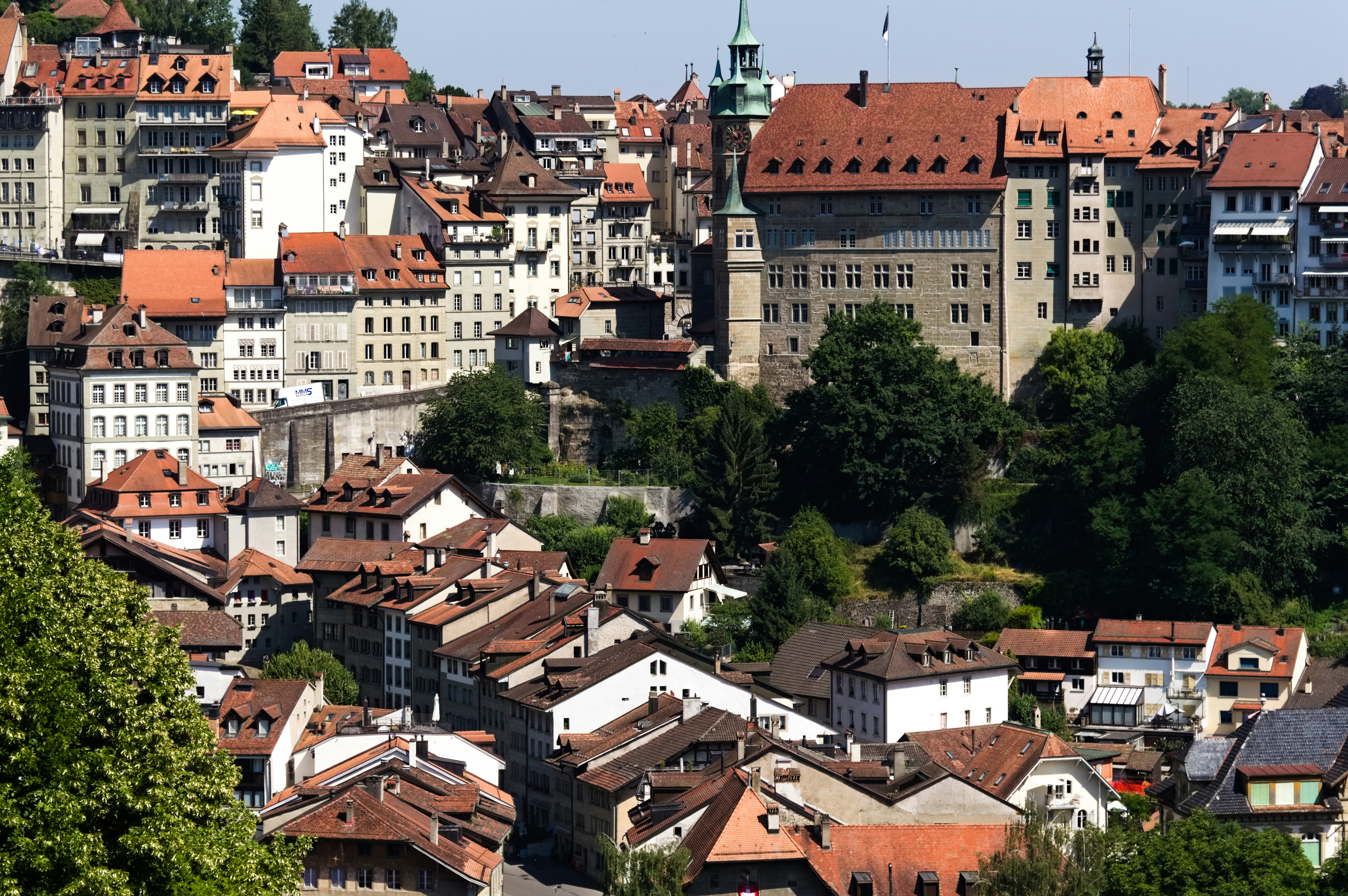Red-tiled rooftops and castle facades cascade through a sunlit hillside town