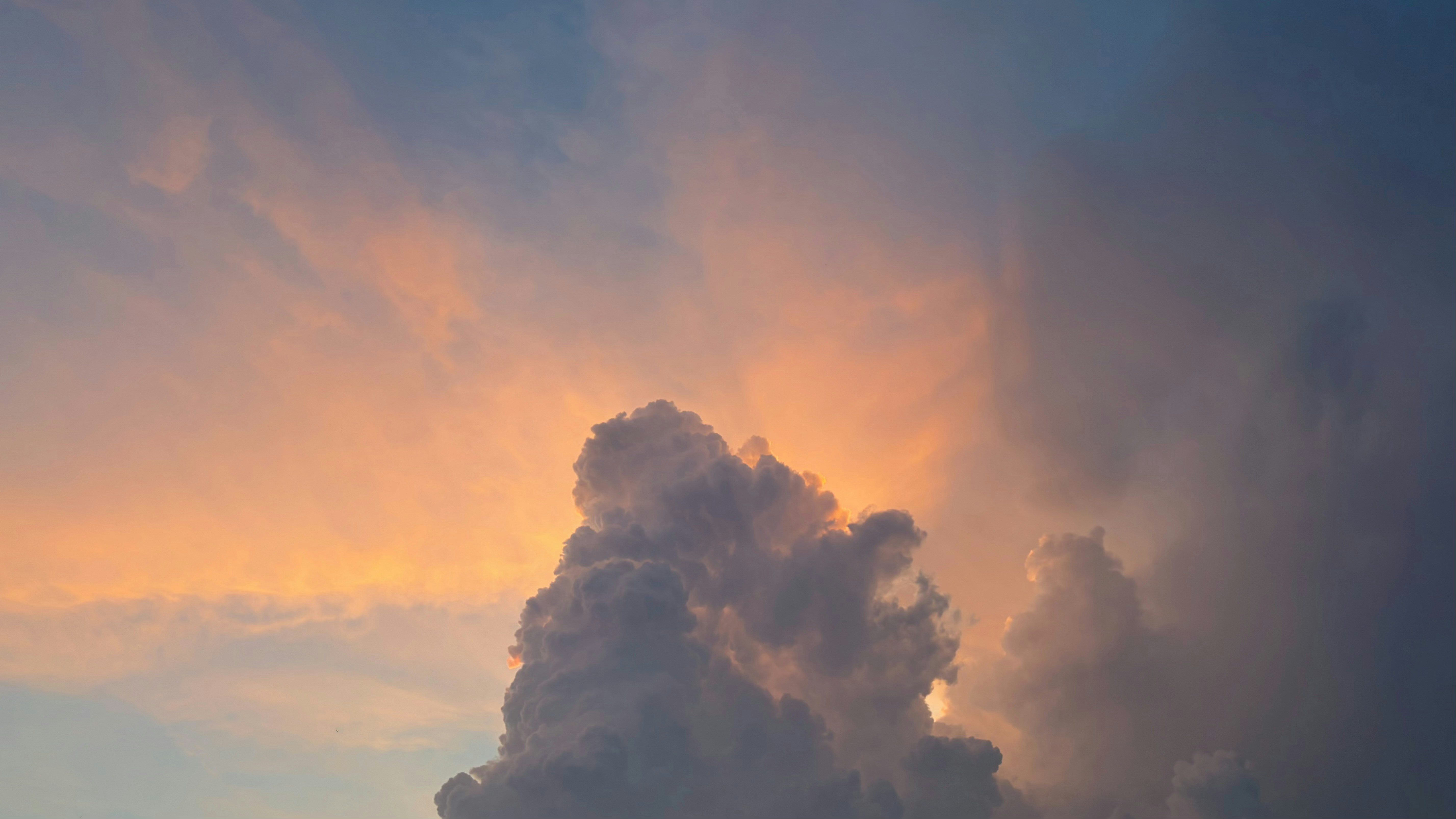 Soft-angled sunset sky with dramatic clouds glowing orange and pink, creating a tranquil landscape-forward composition.