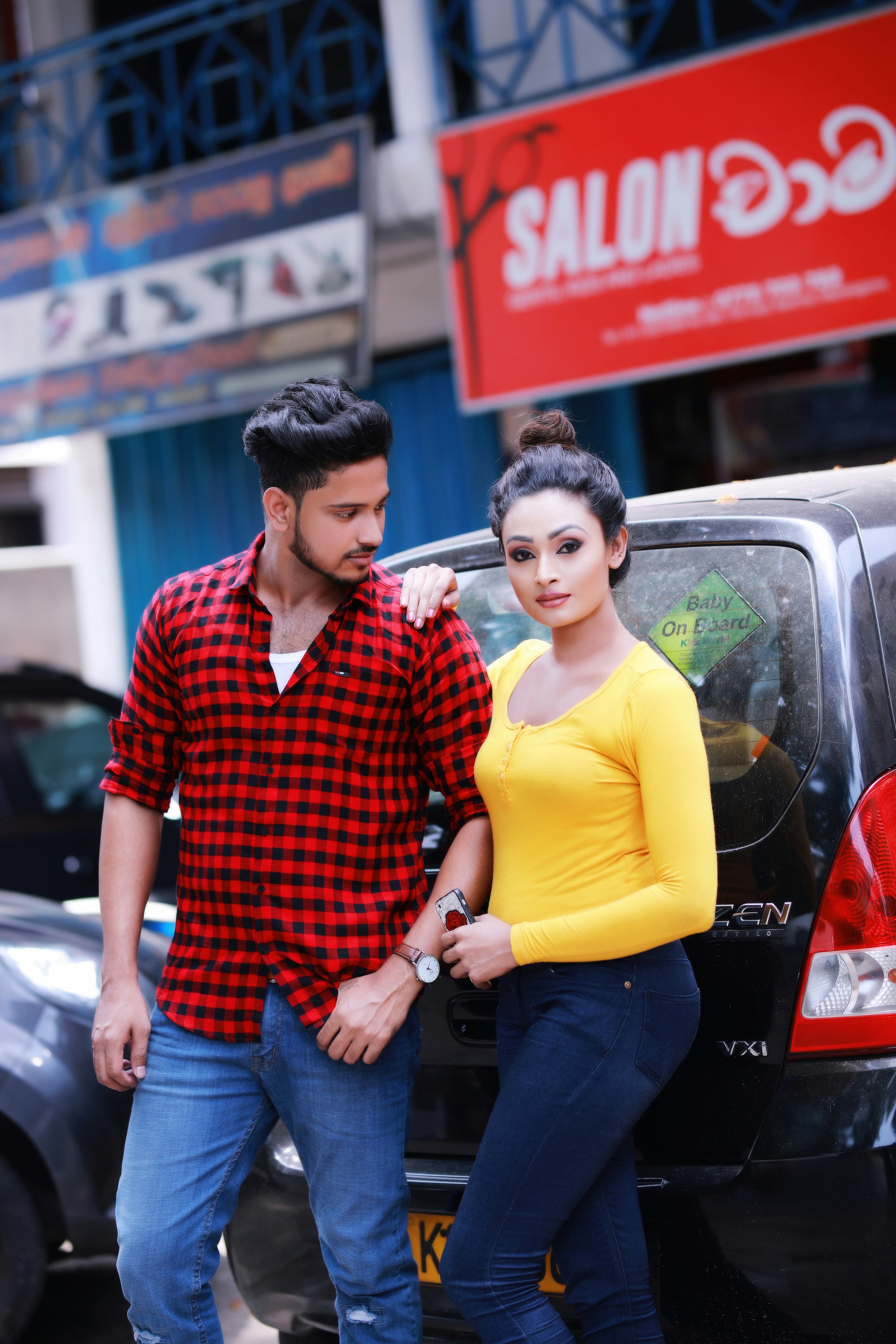 Two Casual Stride: A Couple by the Car Under Neon Salon Signs