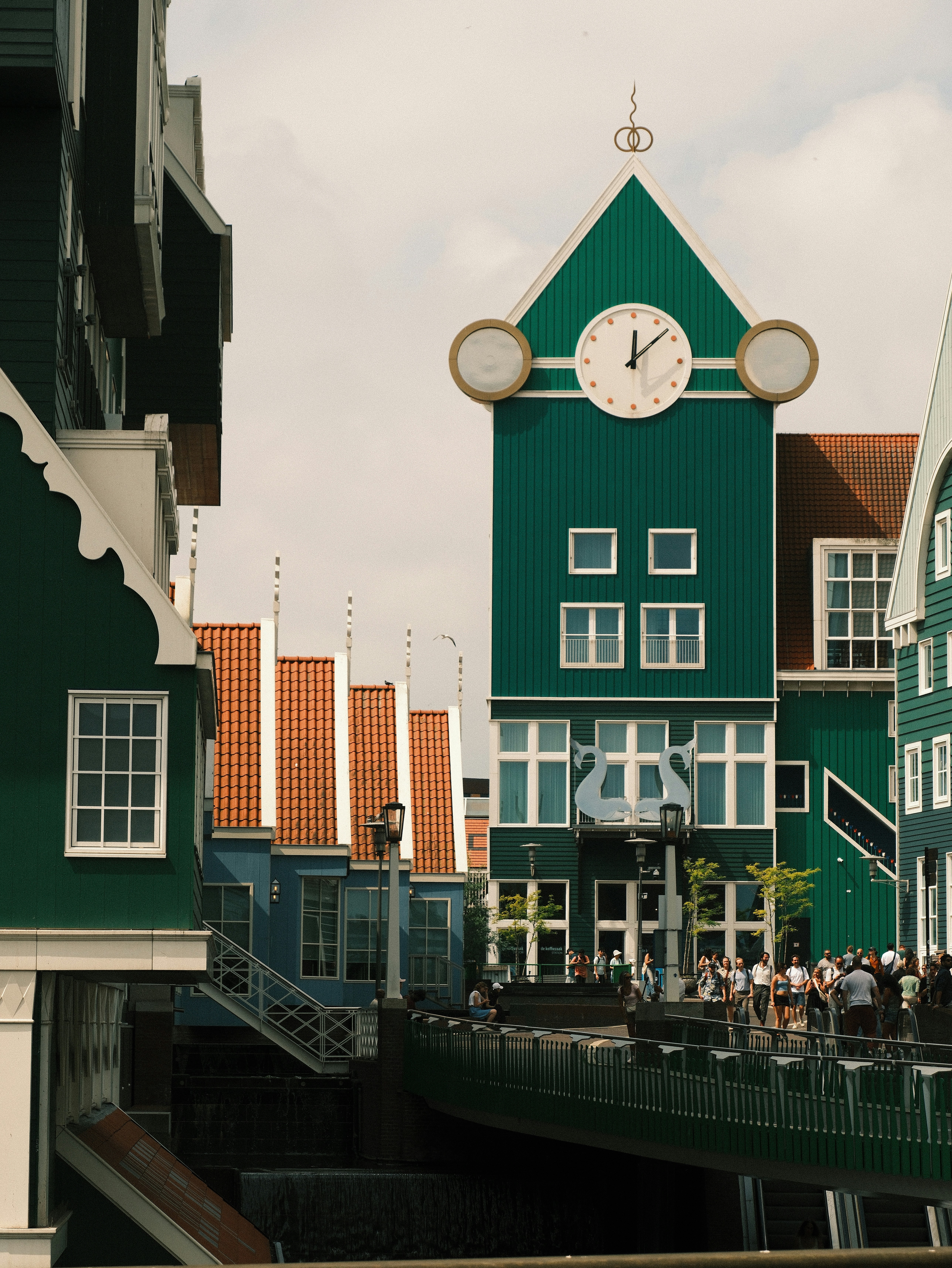 Clocktower Square: teal facades and a crowd under a sunny sky