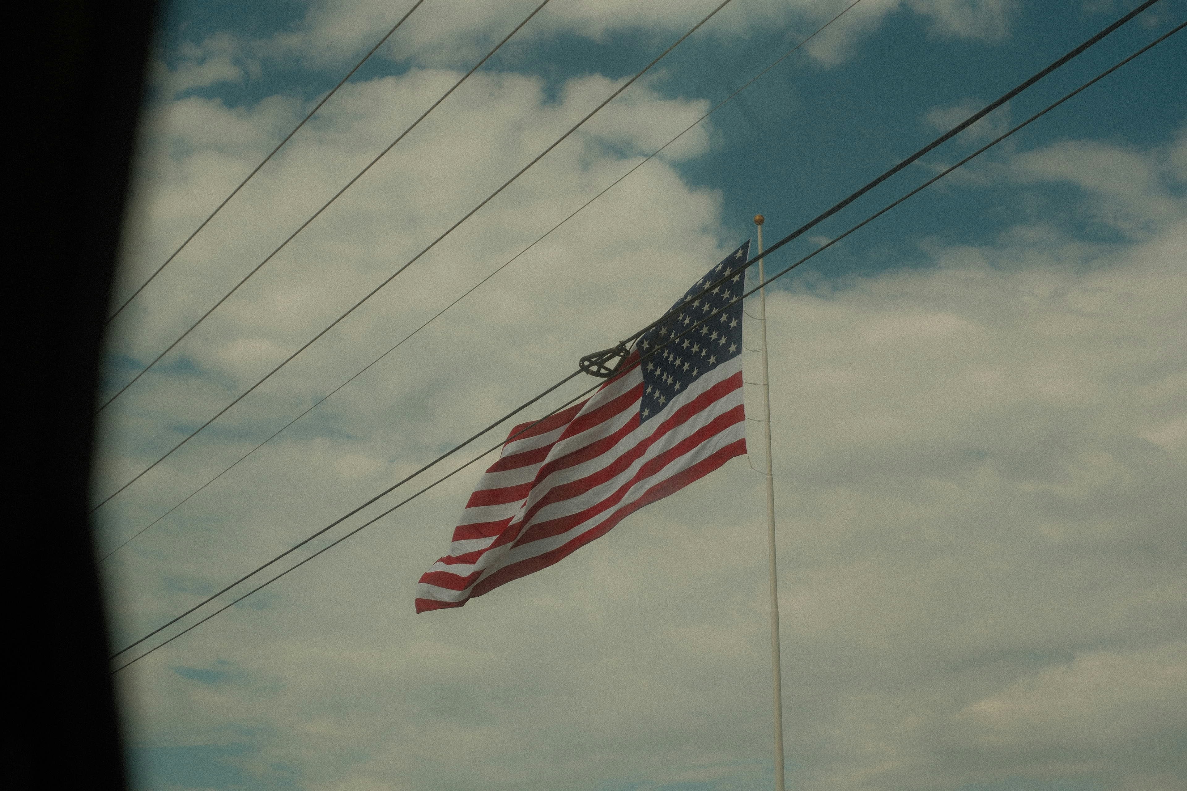 Flag against the sky: a lone American banner tethered to distant power lines