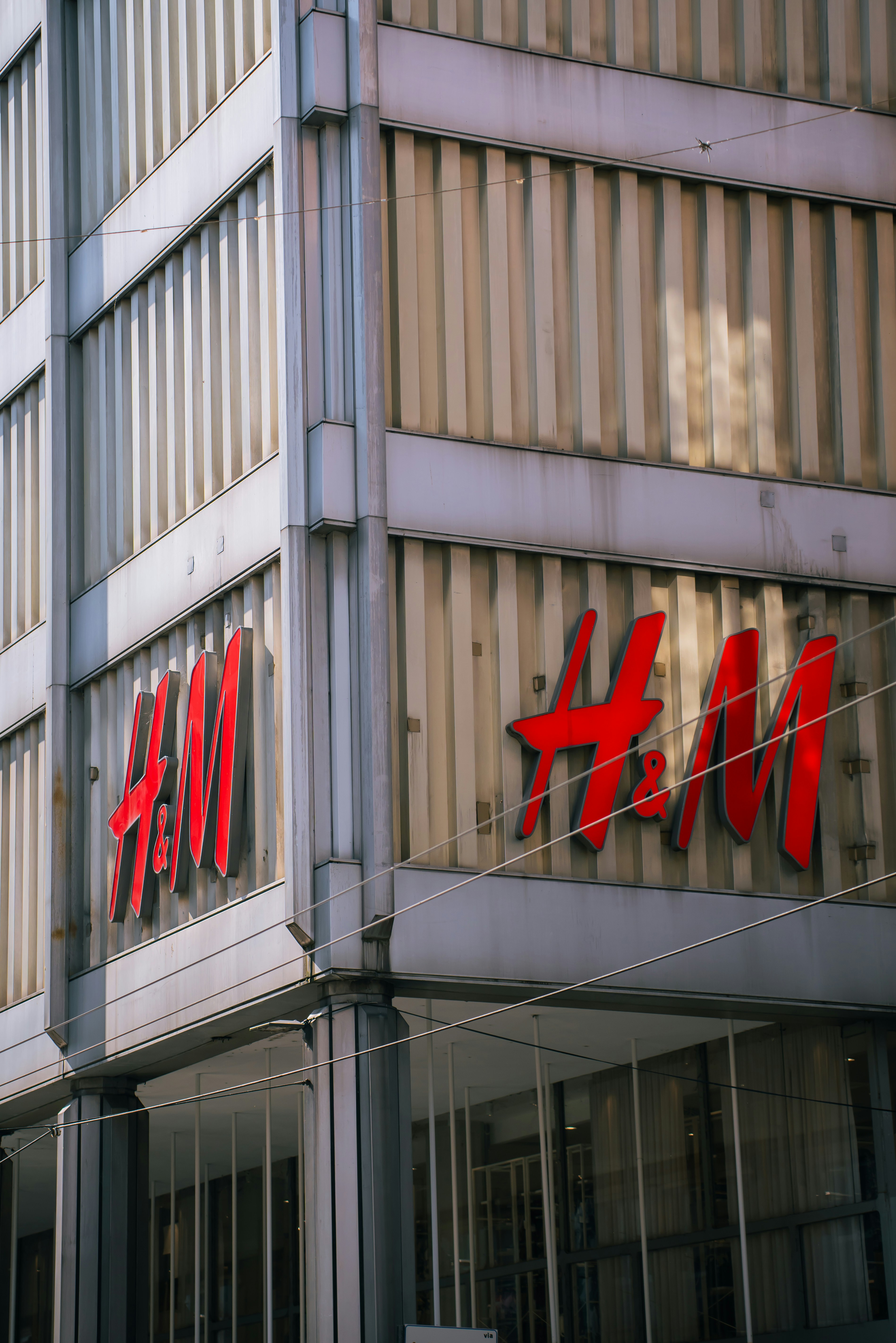 Urban Glow: Red H&M Sign Anchors the Glass Facade
