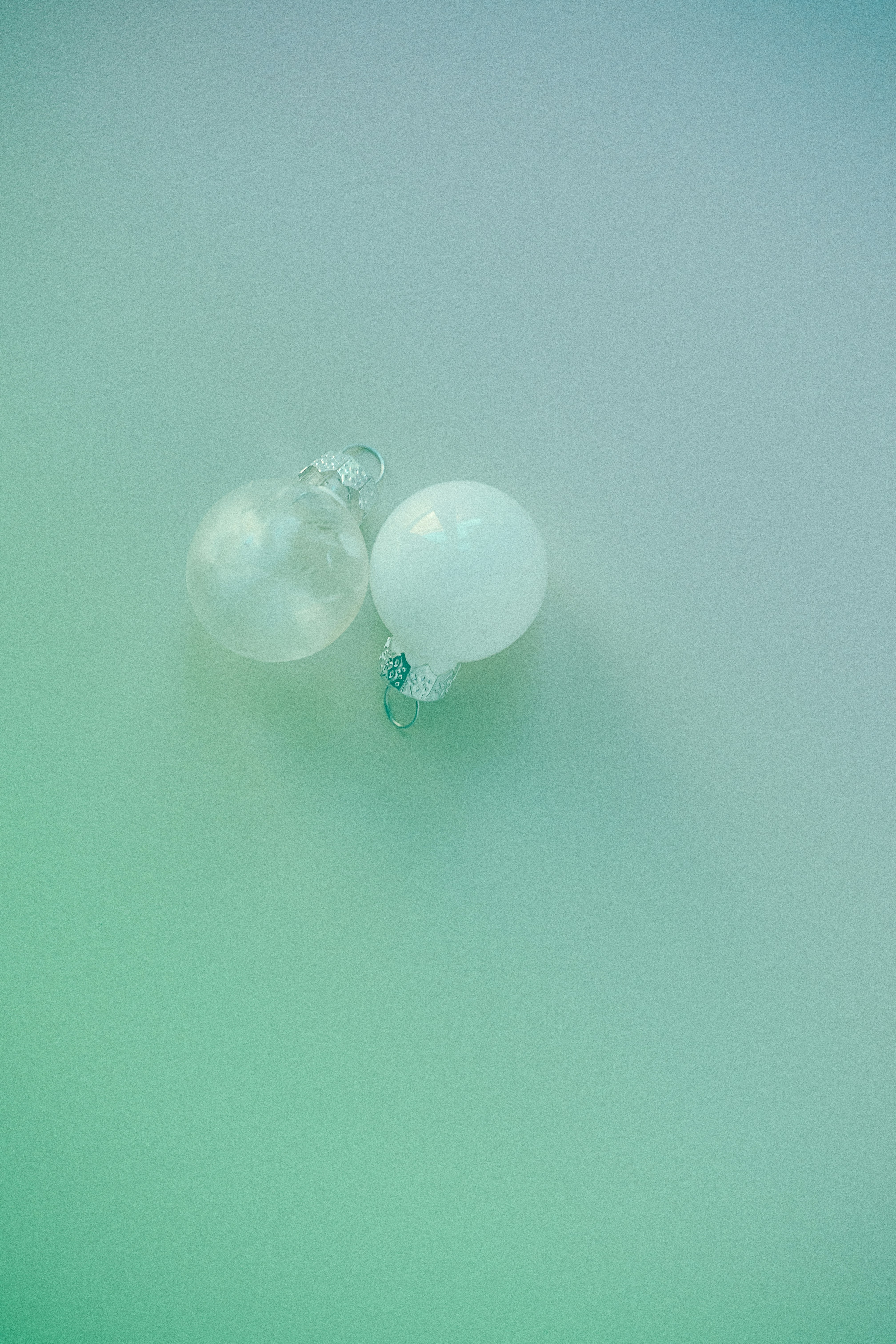 Soft Glimmer: Two Glass Orbs on a Misty Mint Canvas
