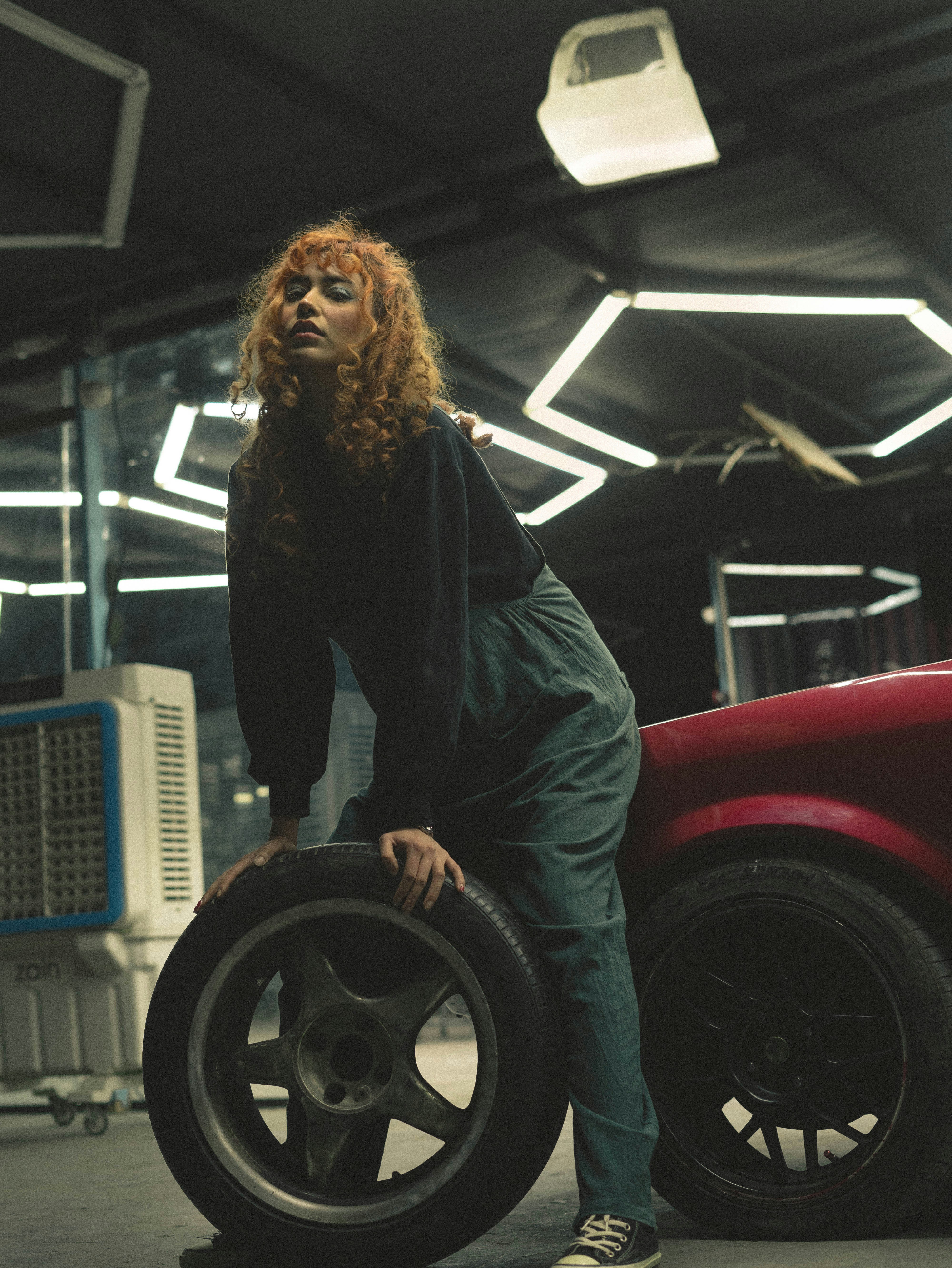 Curved Neon Studio: A Figure Leaning Over a Tire in an Industrial Lightscape