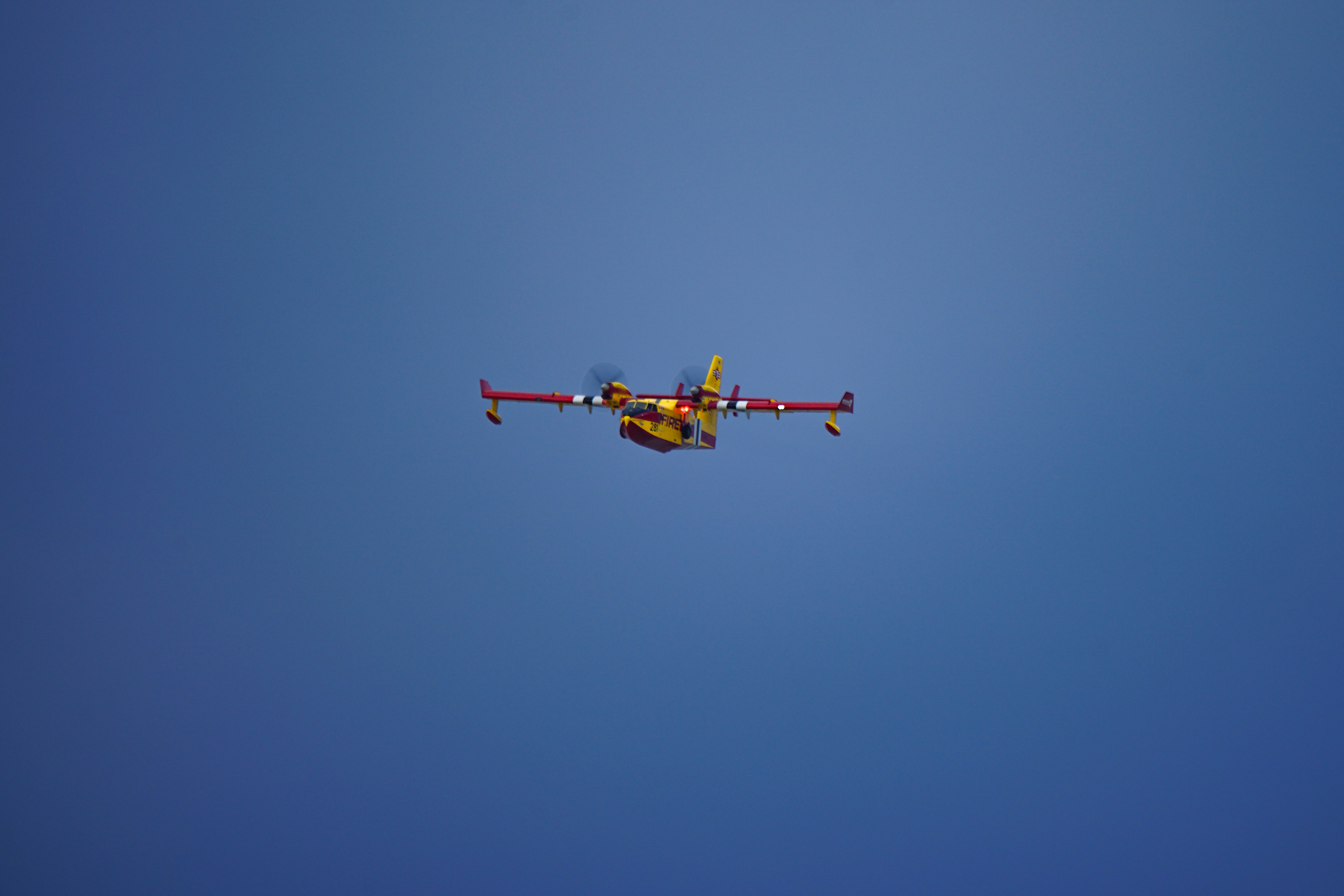 Colorful firefighting aircraft carving a path through a clear blue sky