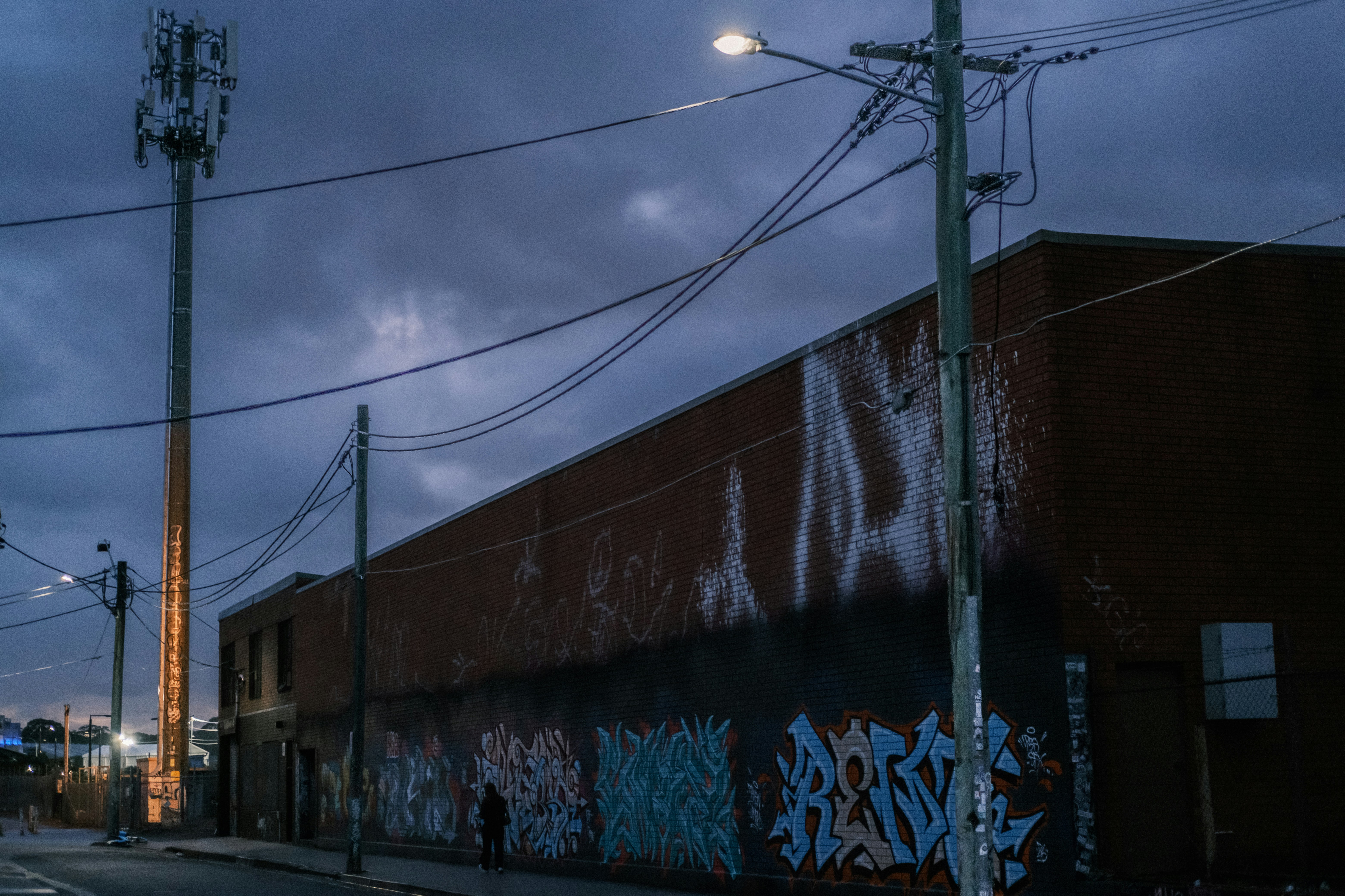 Graffiti-etched Warehouse Under Twilight Streetlight