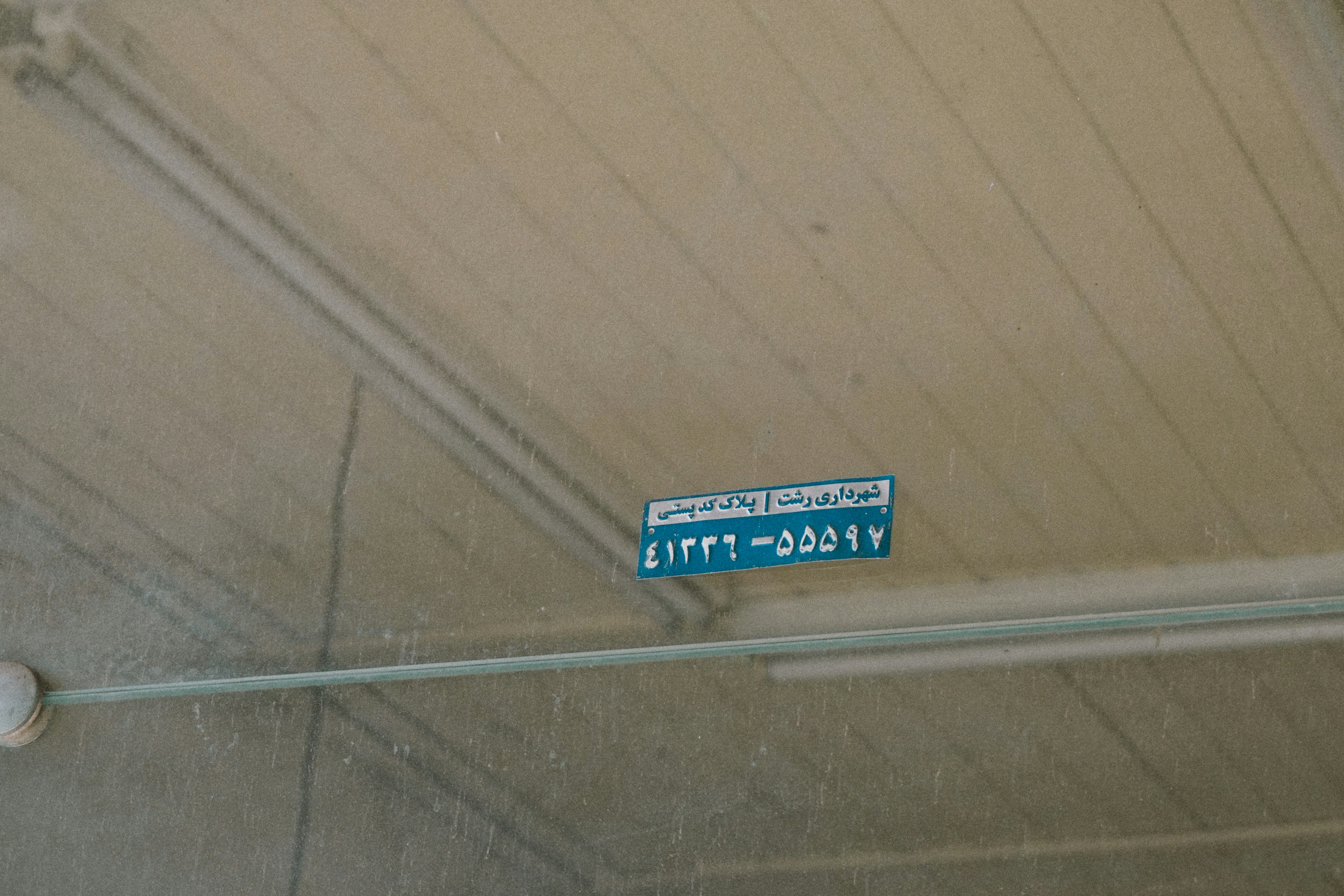 Blue Persian Sign Adrift on Glass: Urban Ceiling Lines
