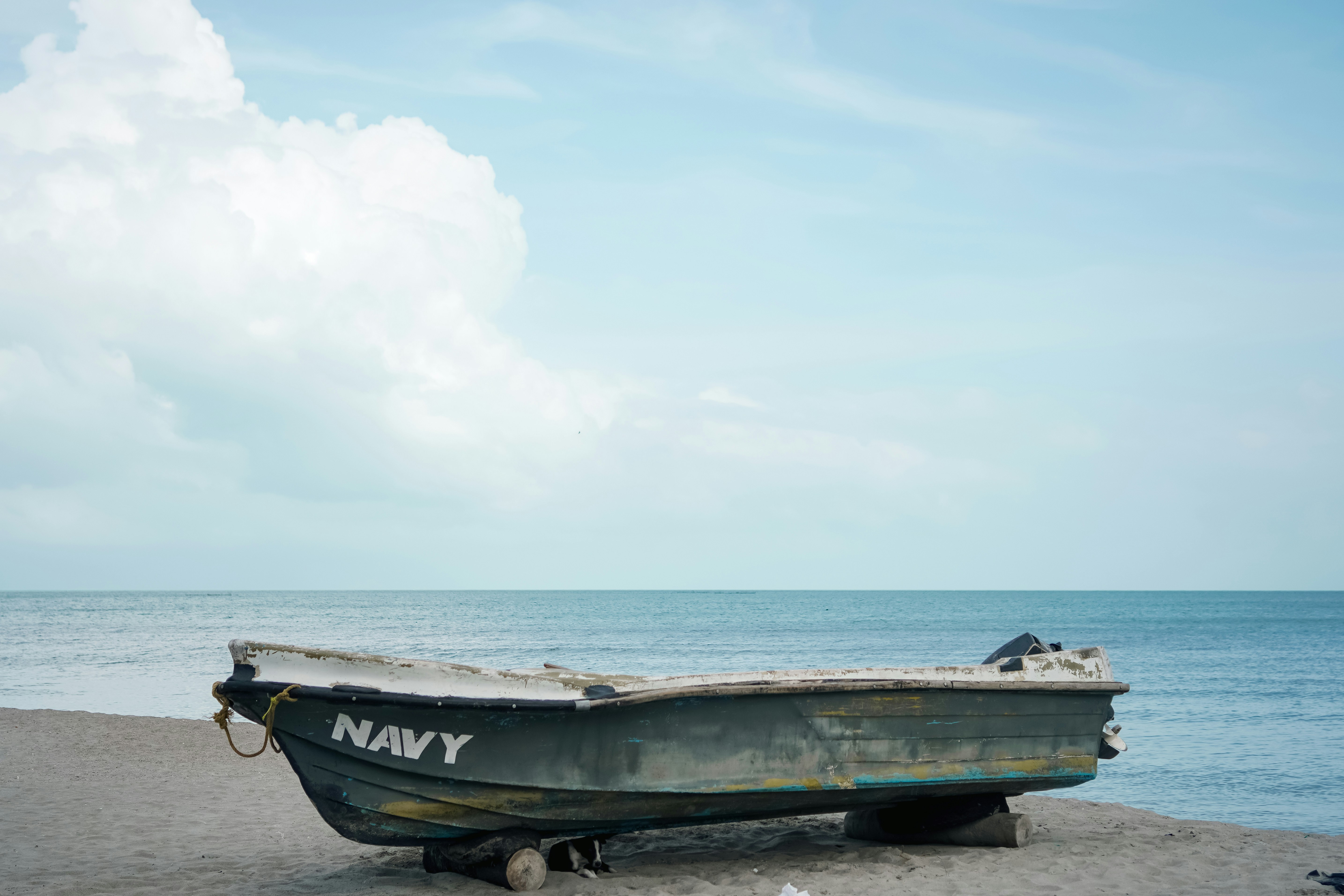 Weathered Navy Boat Resting on Quiet Beach