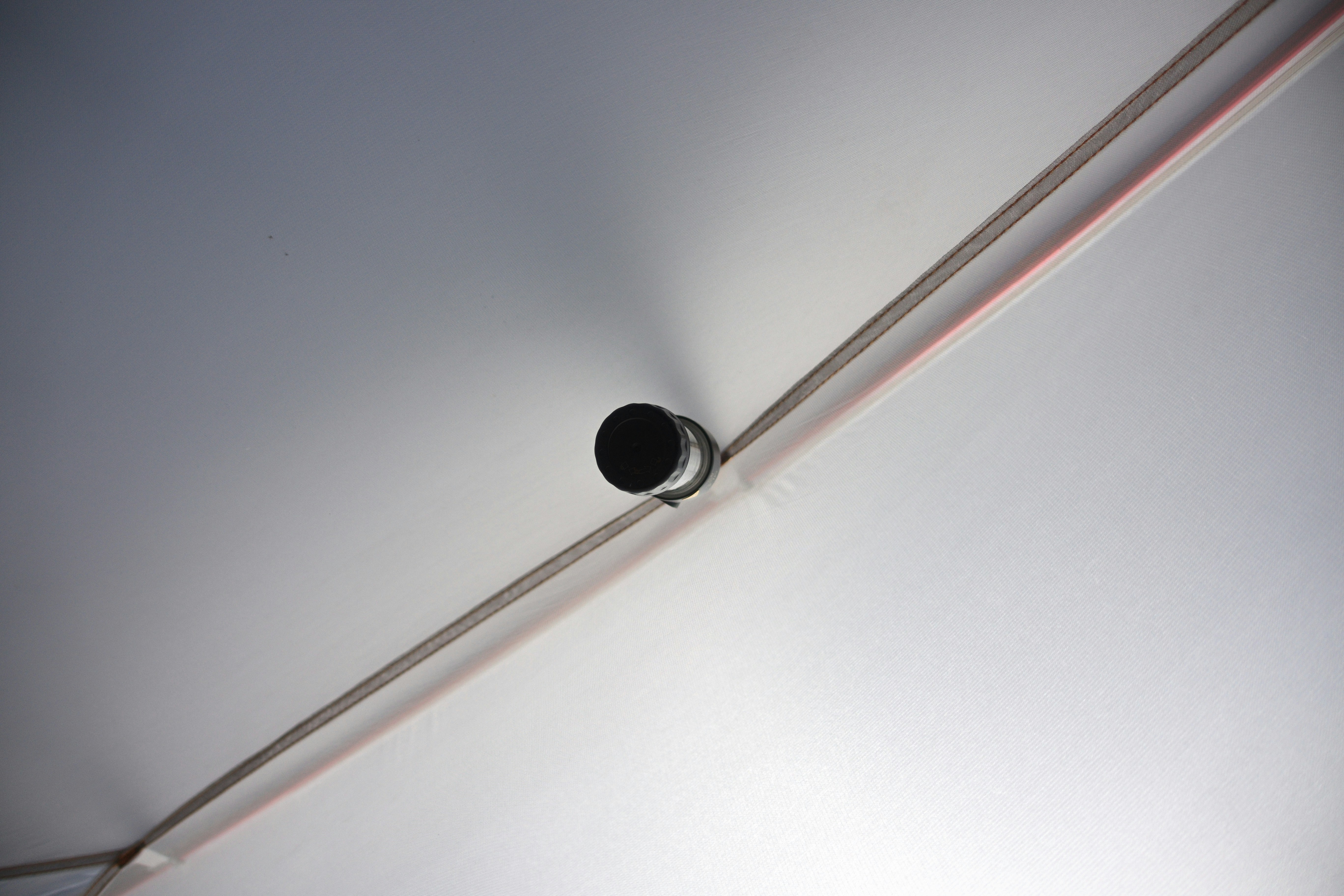 Minimal Ceiling Detail: A Single Bolt and Conduit Crossing a White Plane