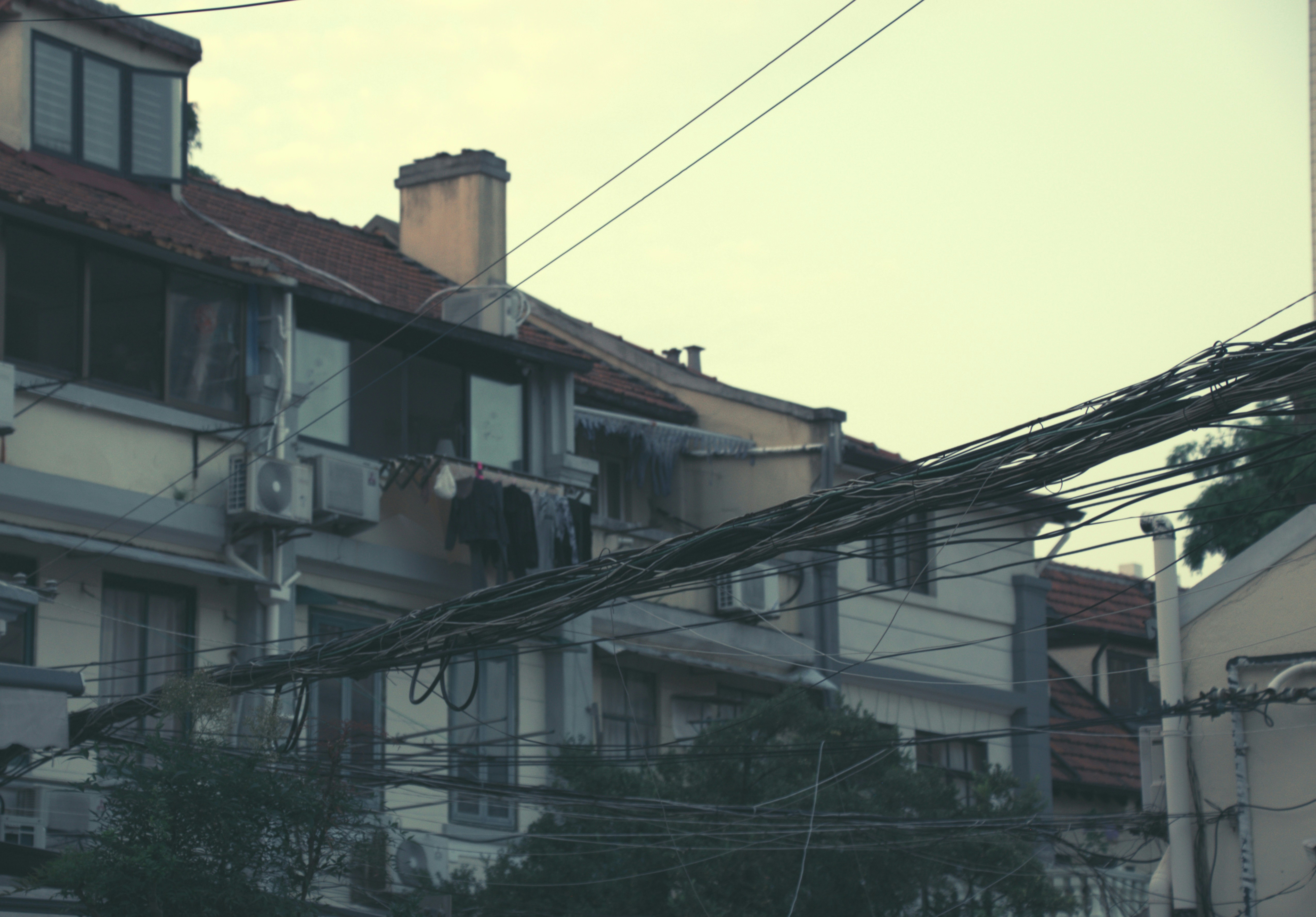 Urban Rooftop Tangle: Wires and Distant Chimneys
