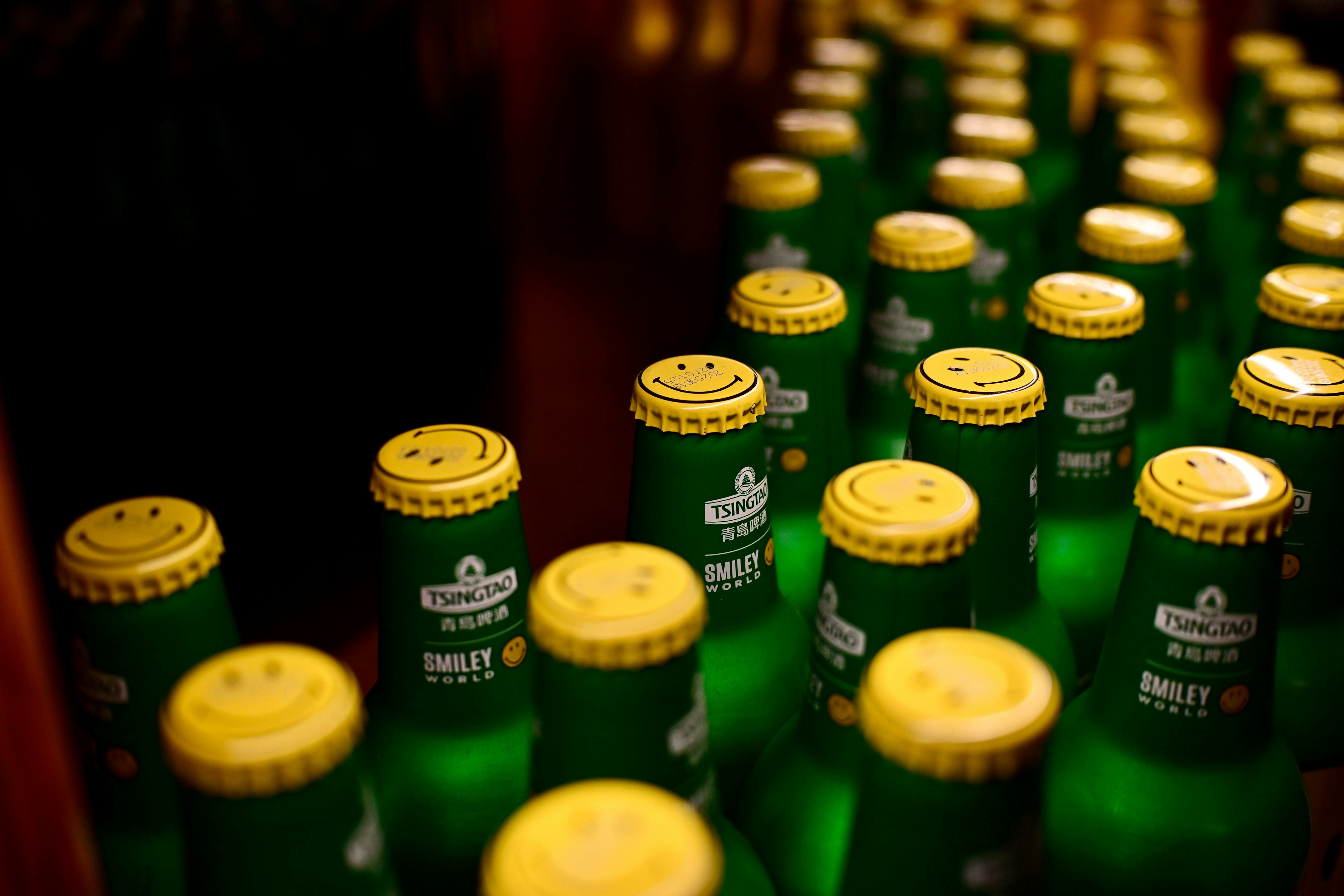 Row of Green Bottles with Yellow Caps in Dim Lighting
