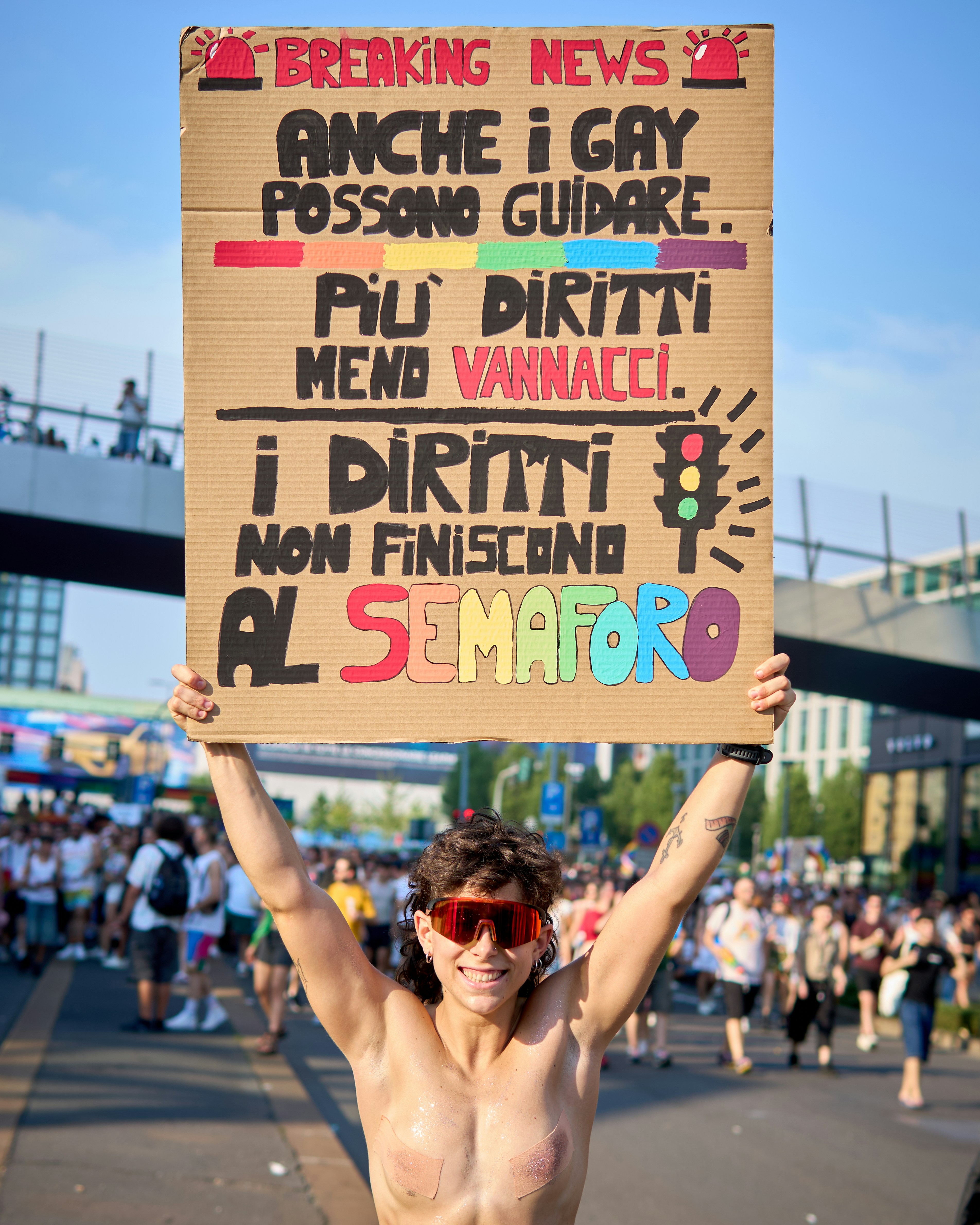 Protester Lifts a Cardboard Message Above a Crowded Street